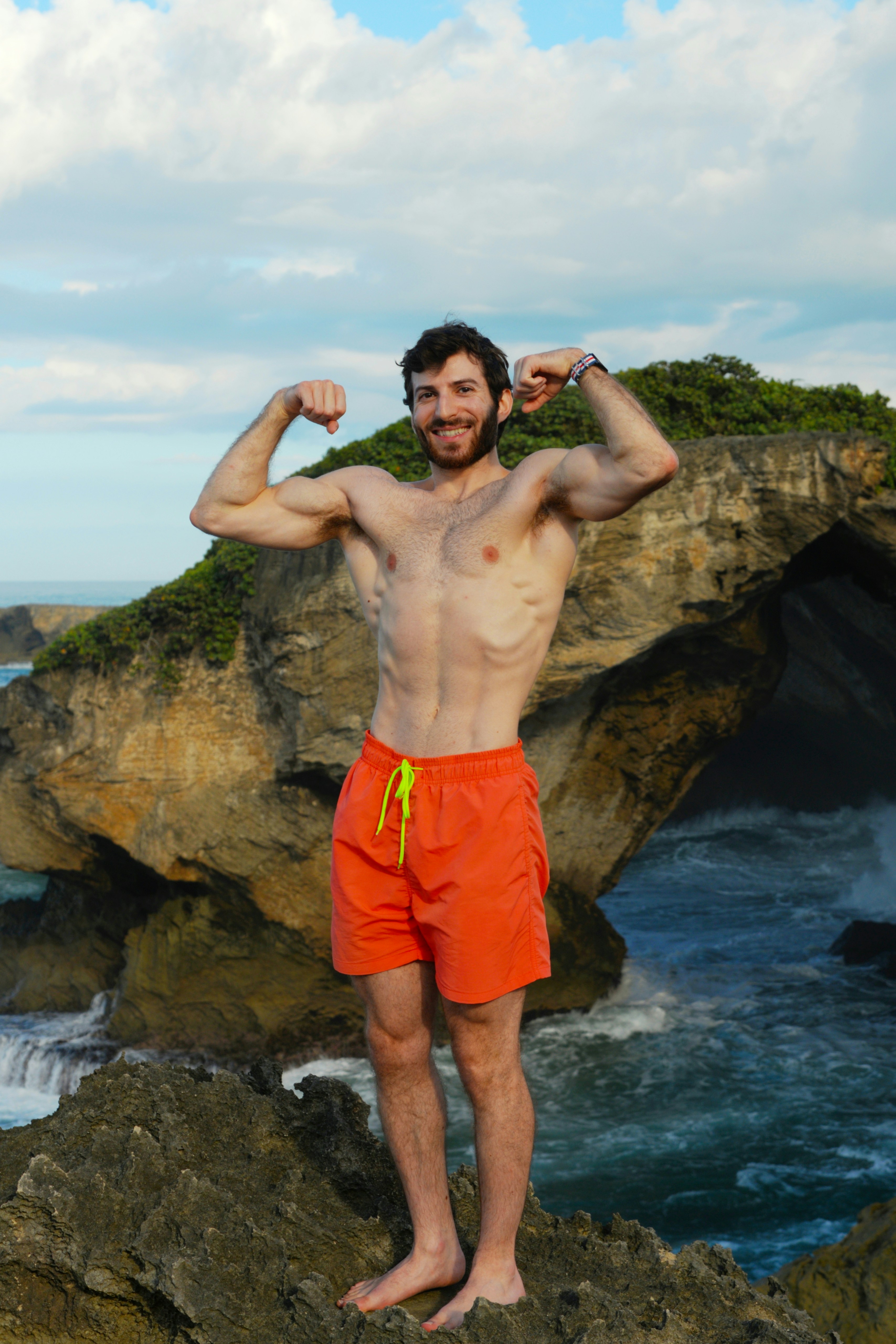 A muscular man flexes his muscles near the ocean. photo – Free Portrait ...