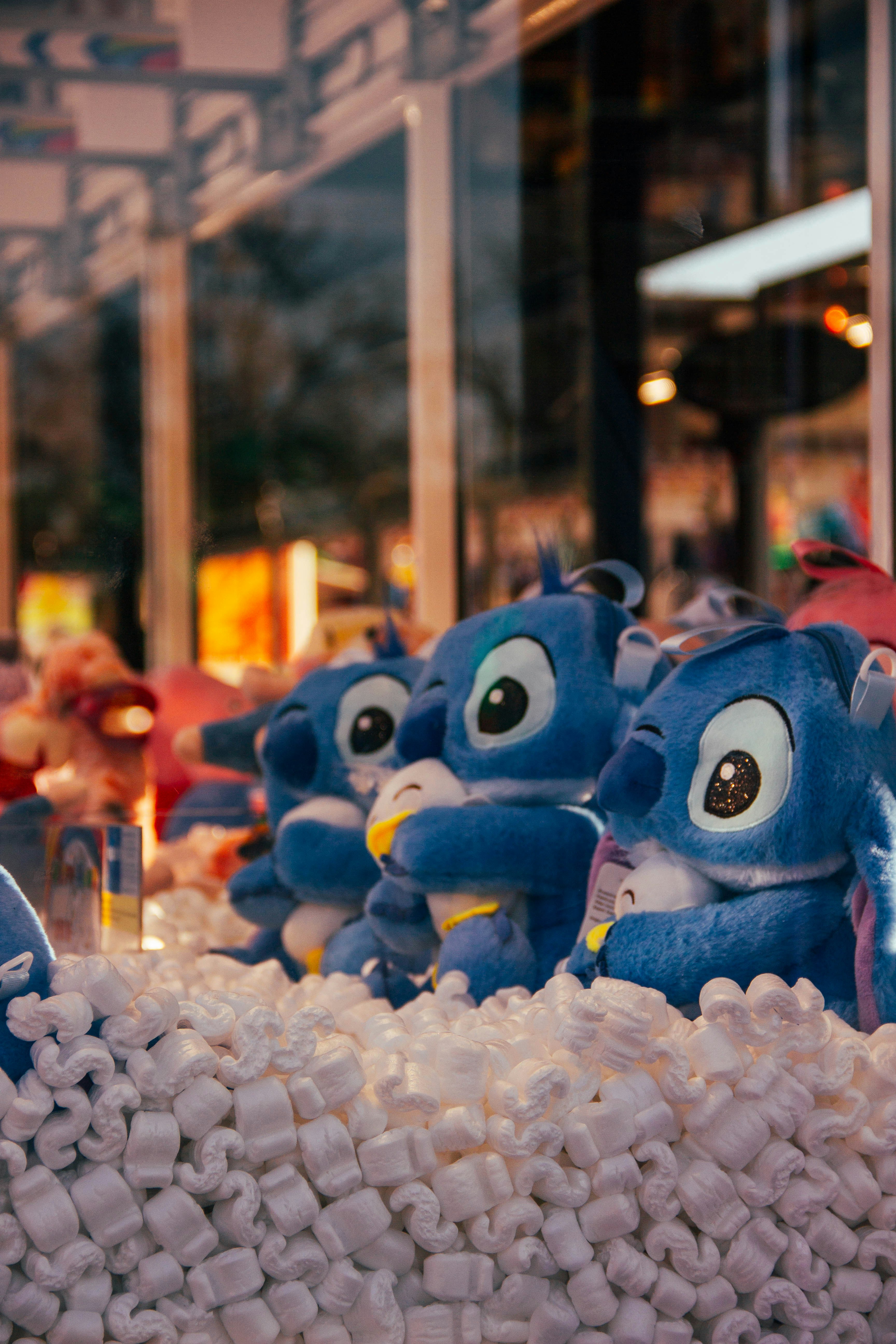 Blue Plush Dragons in a Prize-Claw: Soft Focus Under Warm Arcade Light