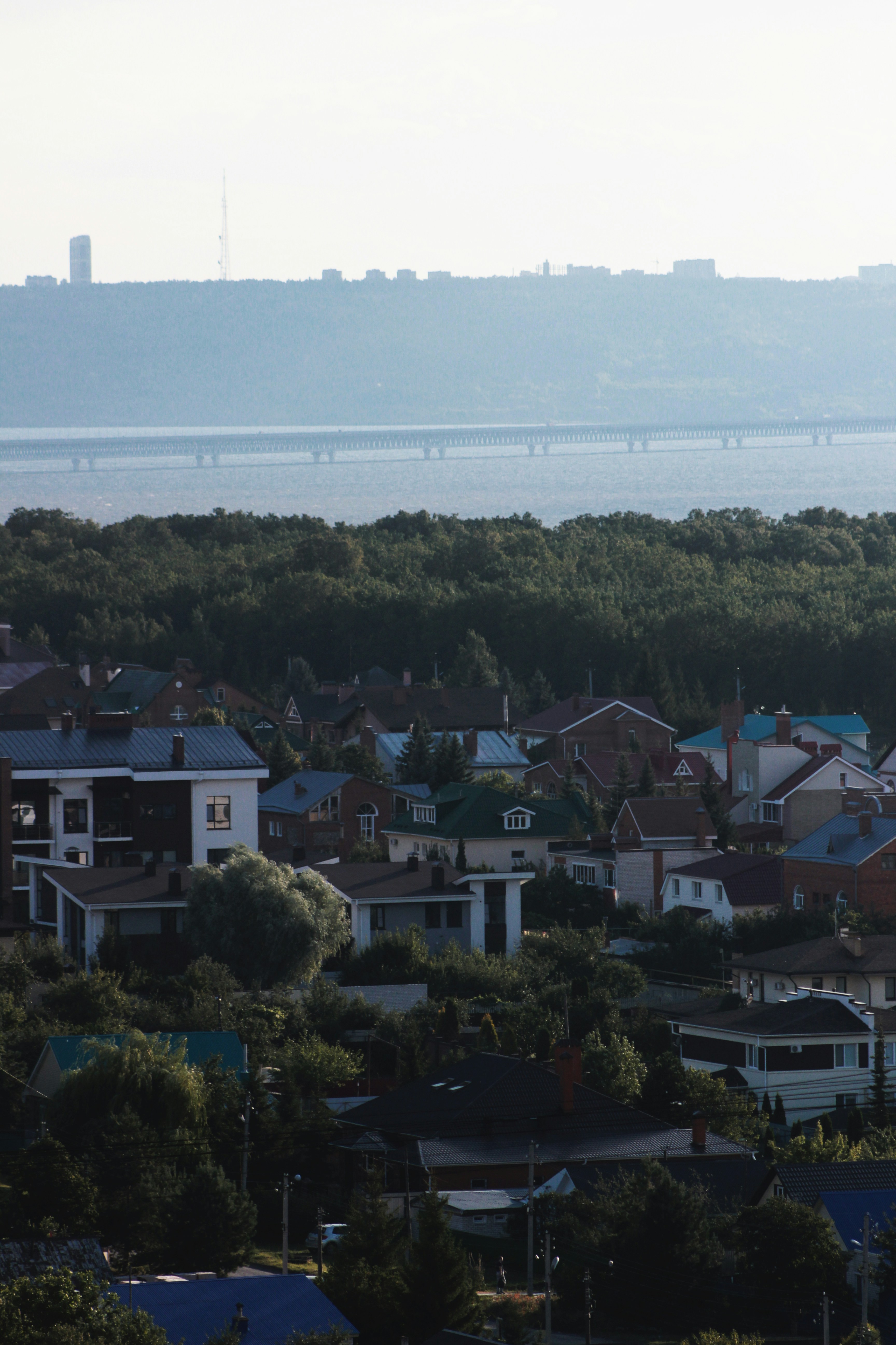 View of a serene riverside town with a bridge in the background under a clear sky.