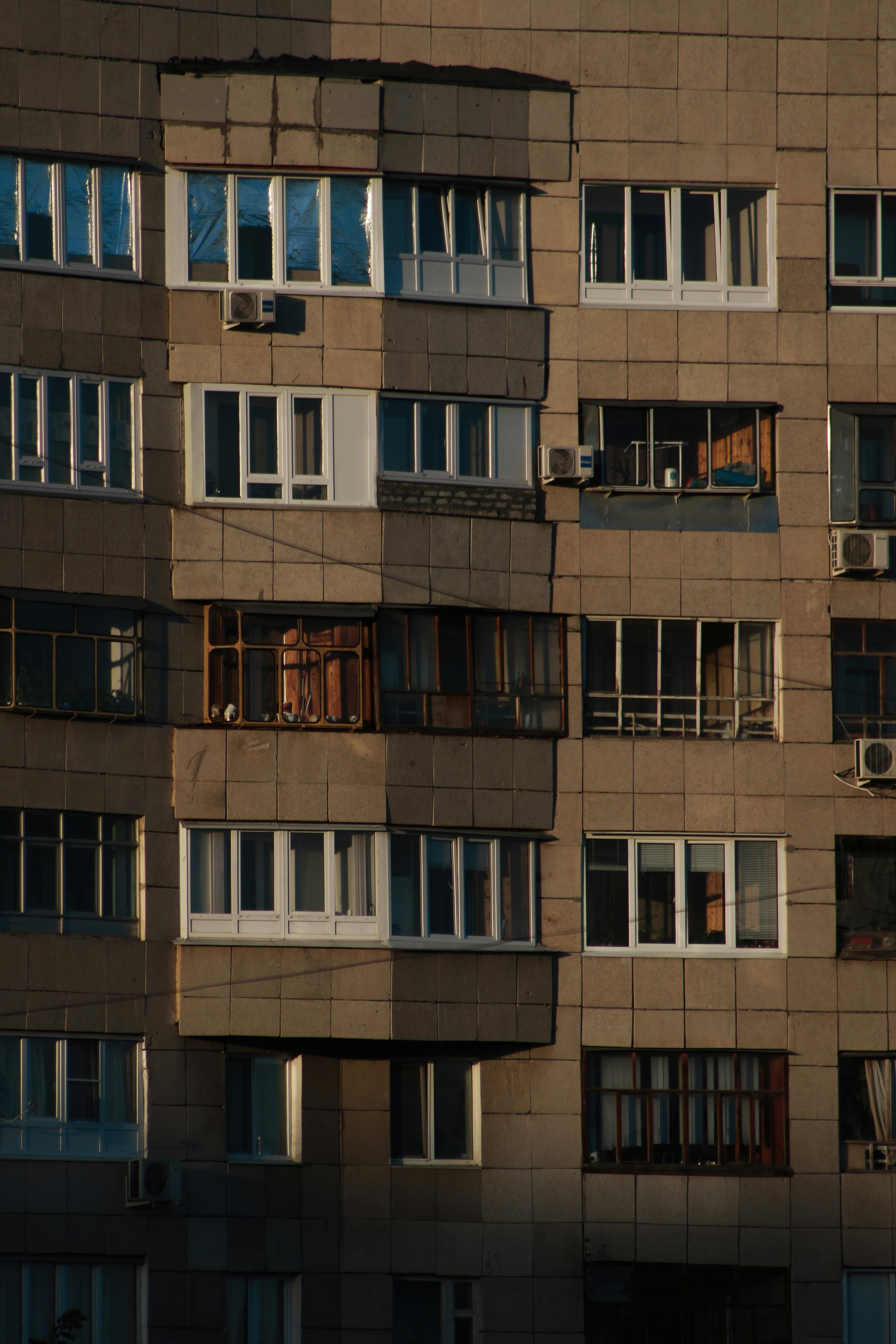 Facade of an apartment building with varied window styles illuminated by warm evening light.