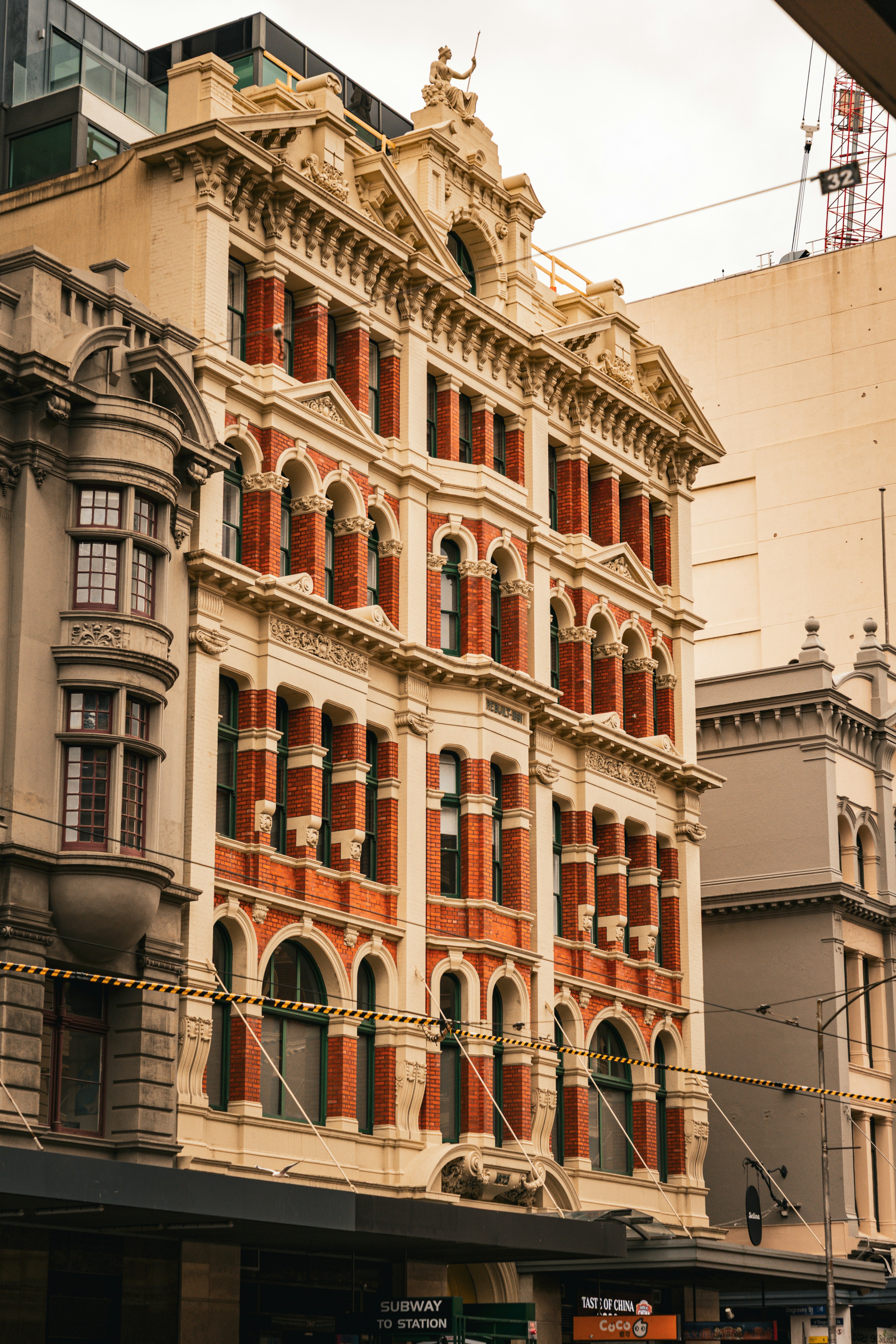 Ornate Edwardian building facade with intricate detailing and red brick accents in an urban setting.