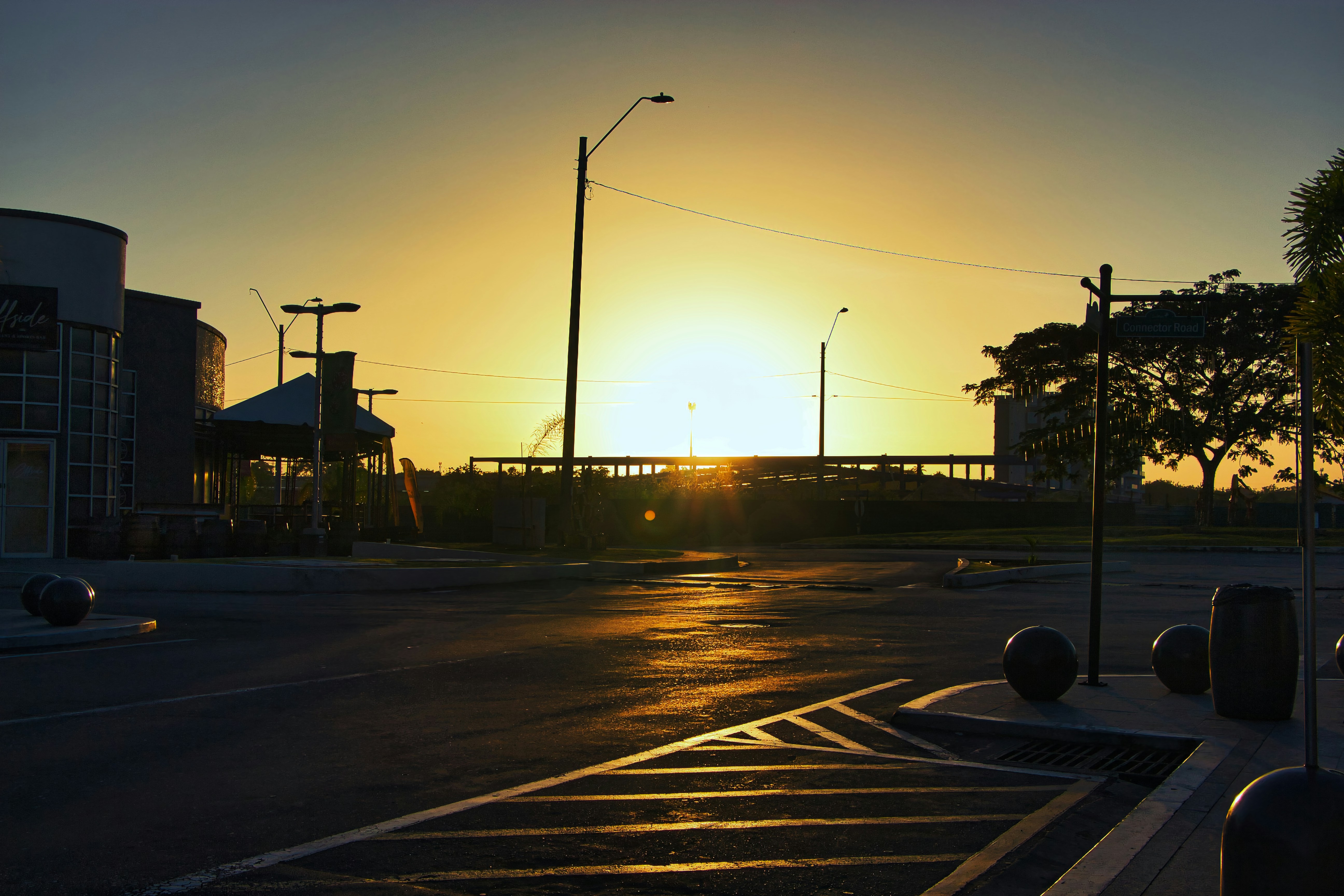 Sun rising over a quiet street, casting long shadows and illuminating the horizon.