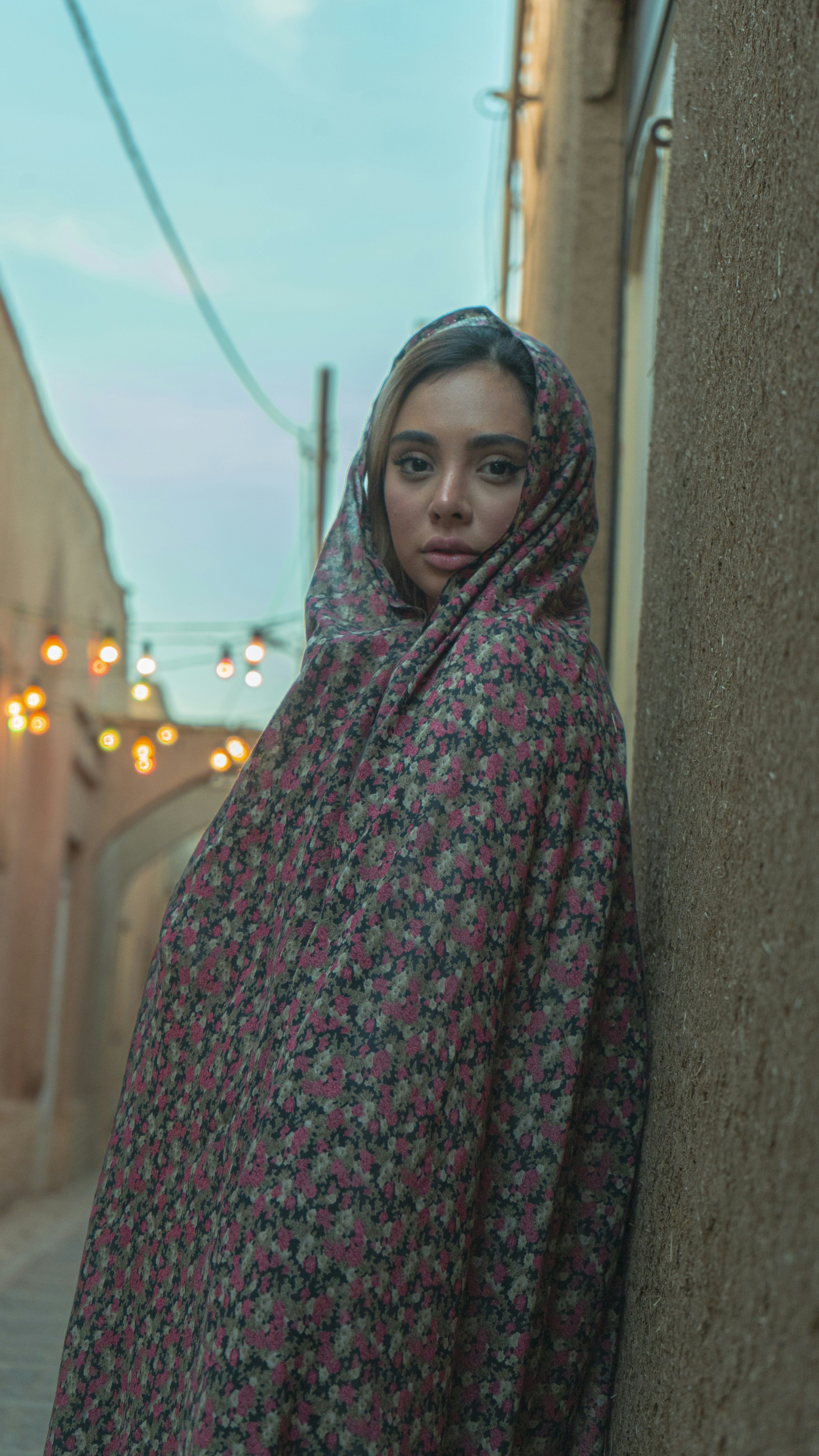 Una mujer con un pañuelo floral en la cabeza posa en un callejón estrecho. foto – Imagen de ...