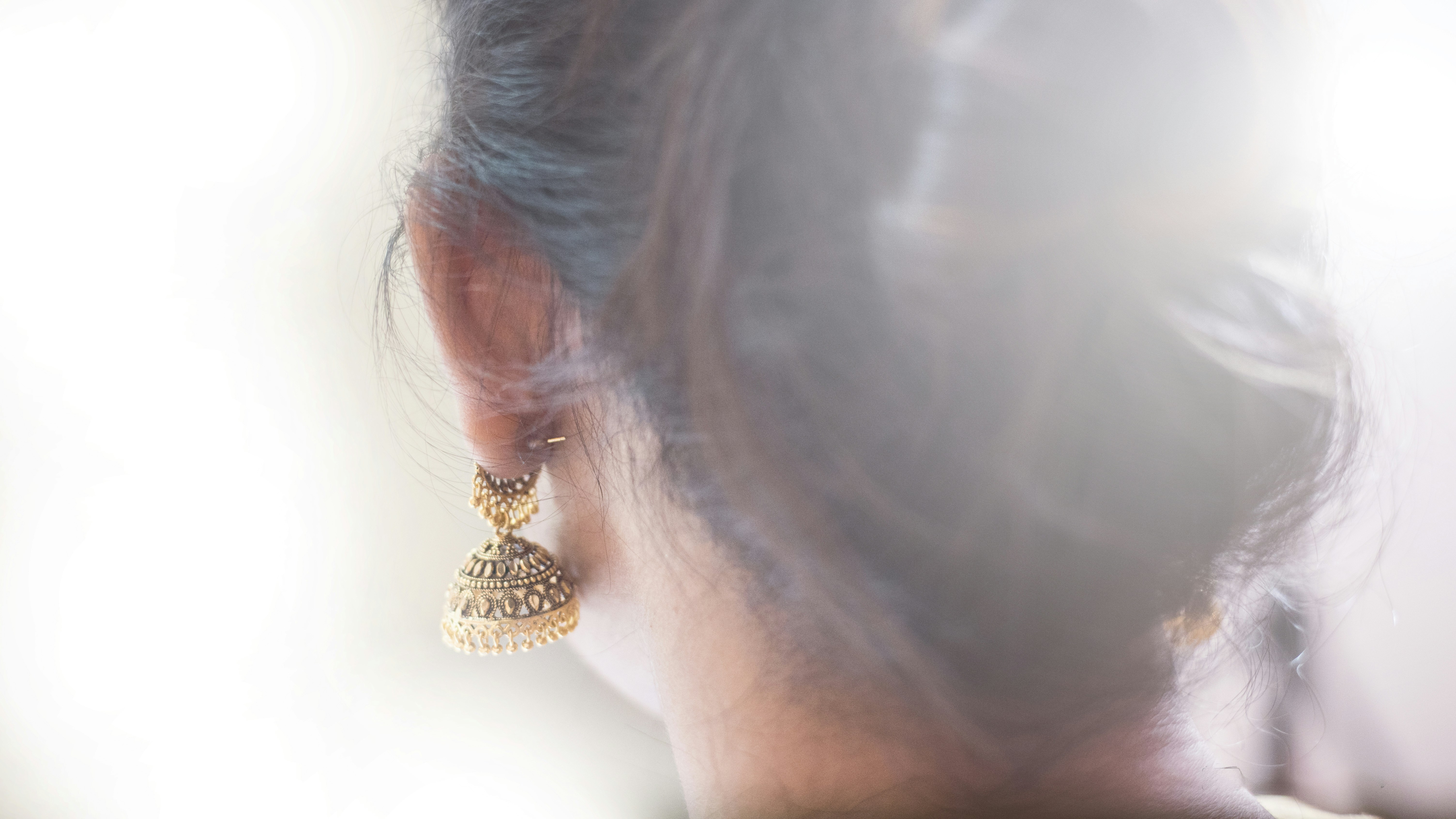 Soft flare on a gold jhumka: a quiet back-portrait in morning light
