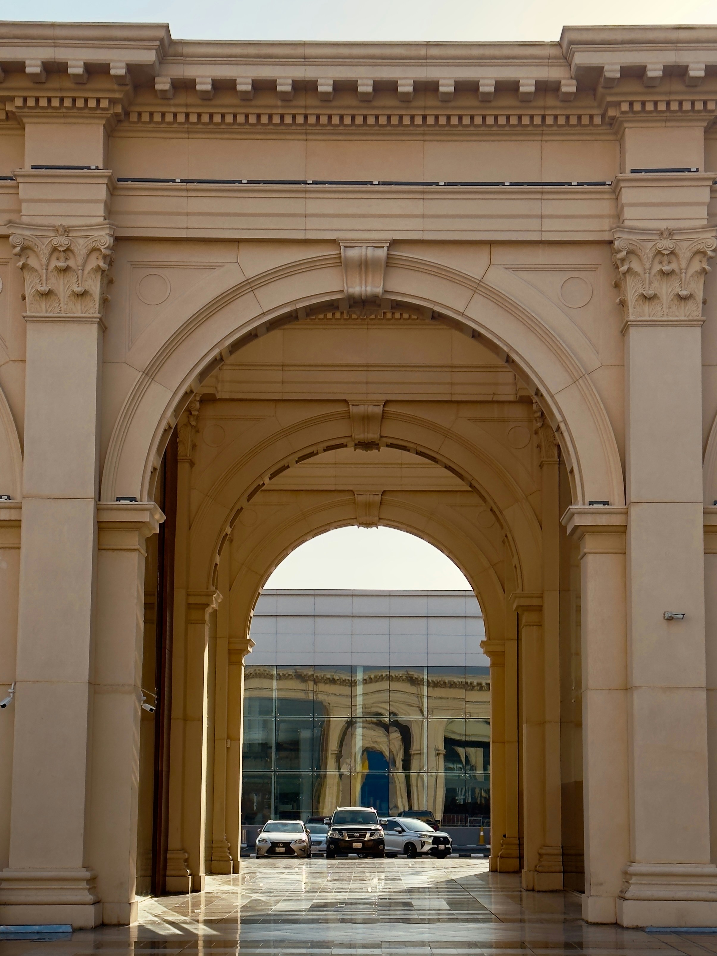 Gateway of Arches: Symmetrical Stone Corridor Framing a Glass-Faced Courtyard