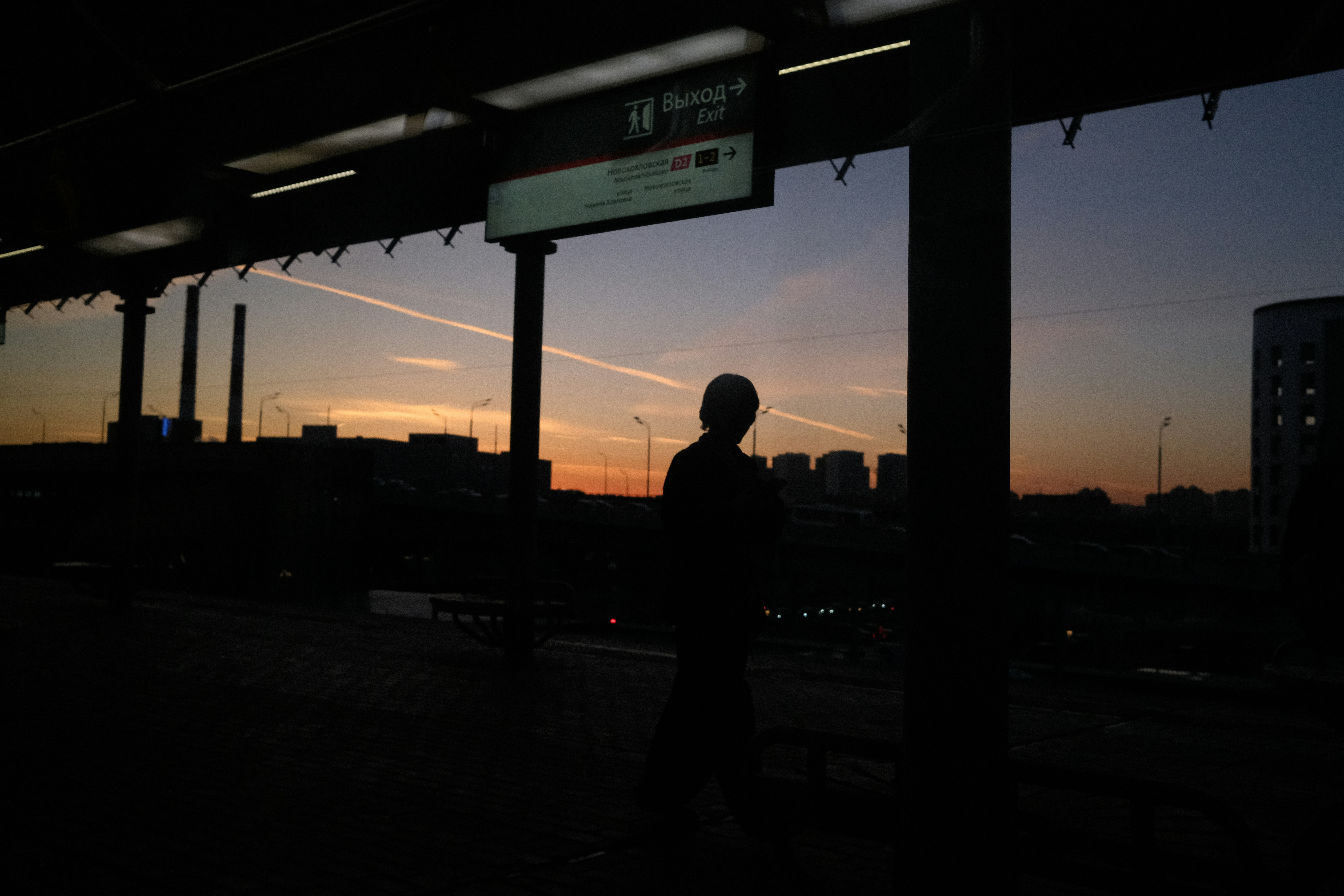 Twilight Silhouette on the Platform: A Quiet Moment Beneath Signage