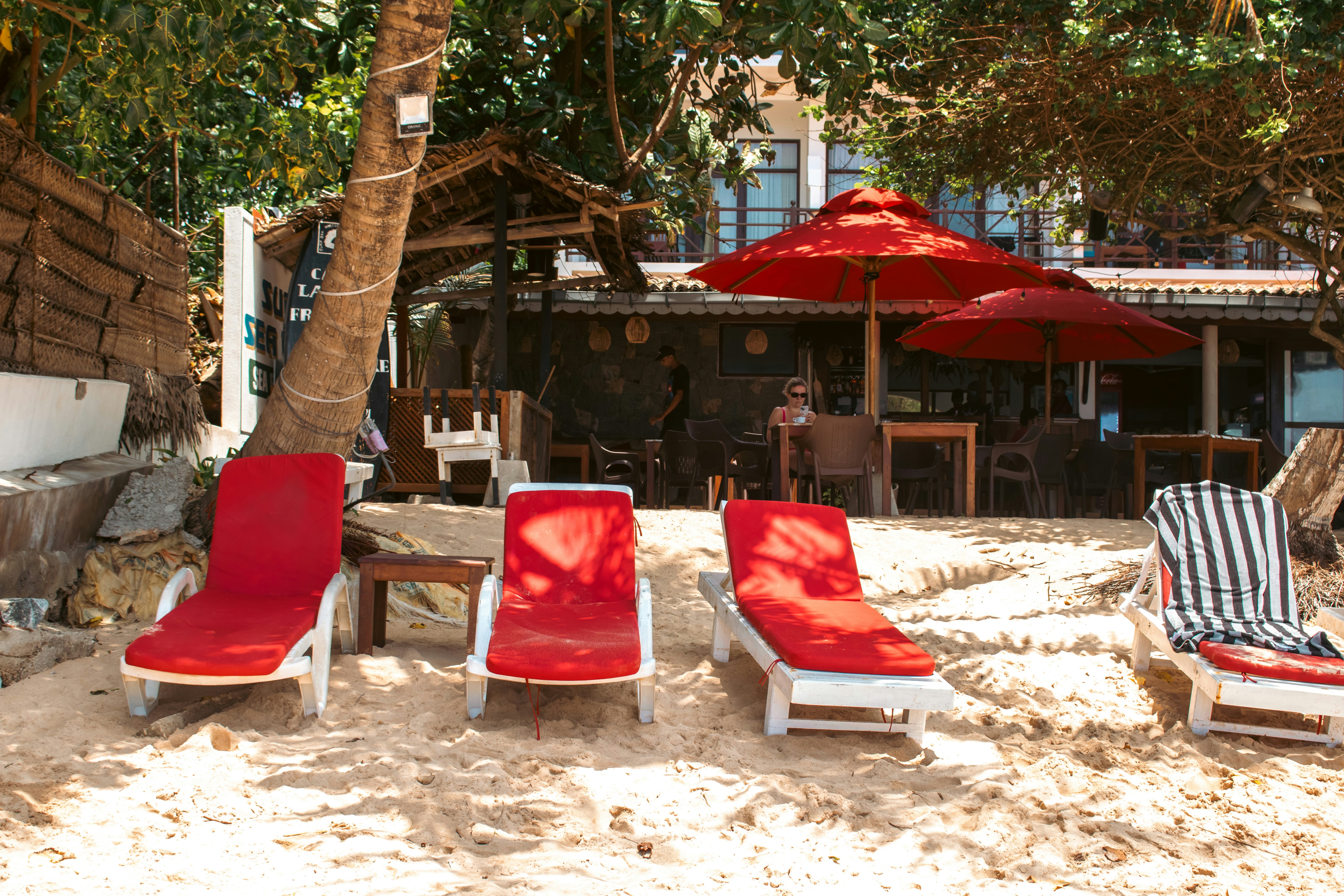 Red and white beach chairs of a shack placed directly on the sand.