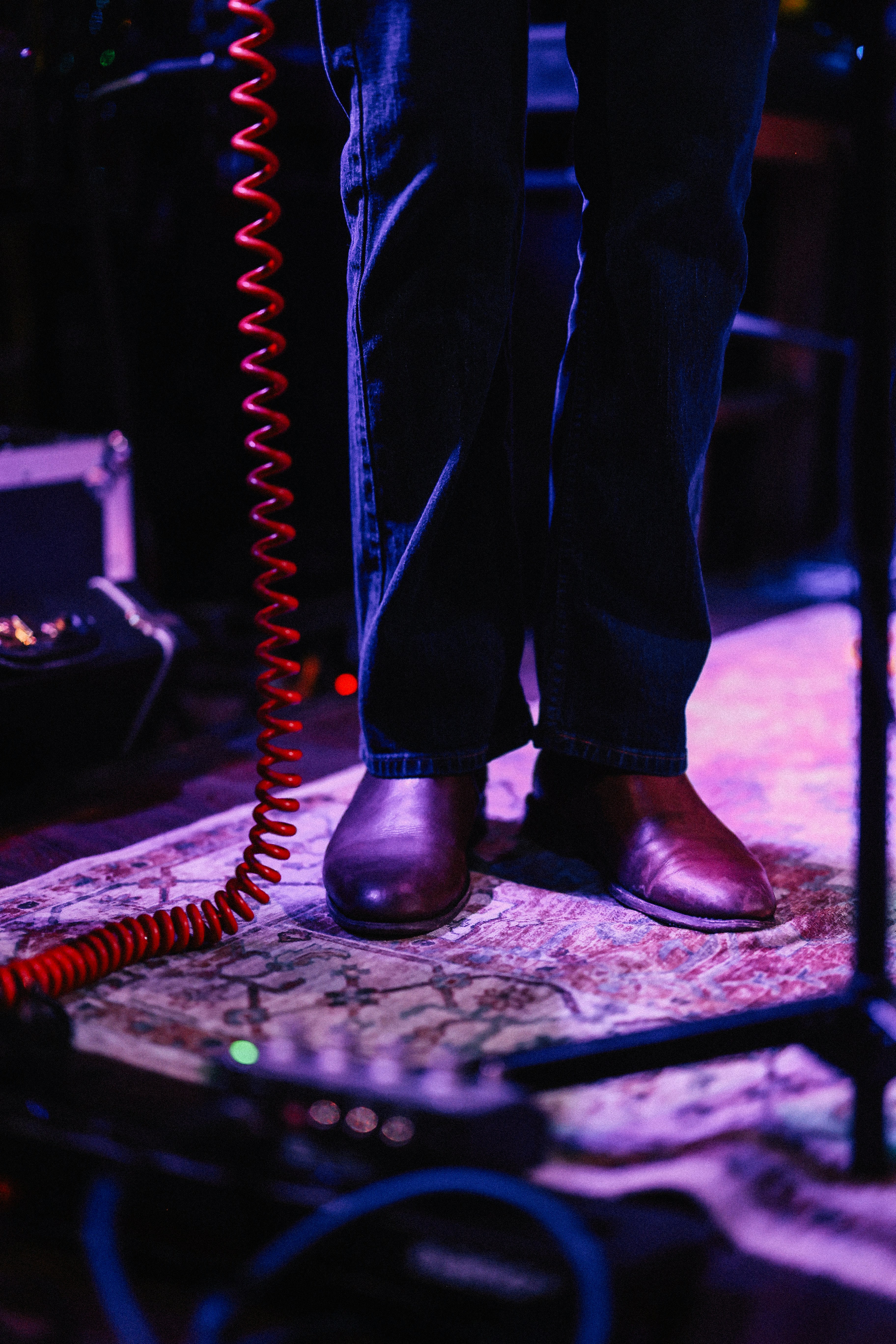 Center-Stage Leather Boots Under Indigo Neon: A Close-Up on Footwear and Cables