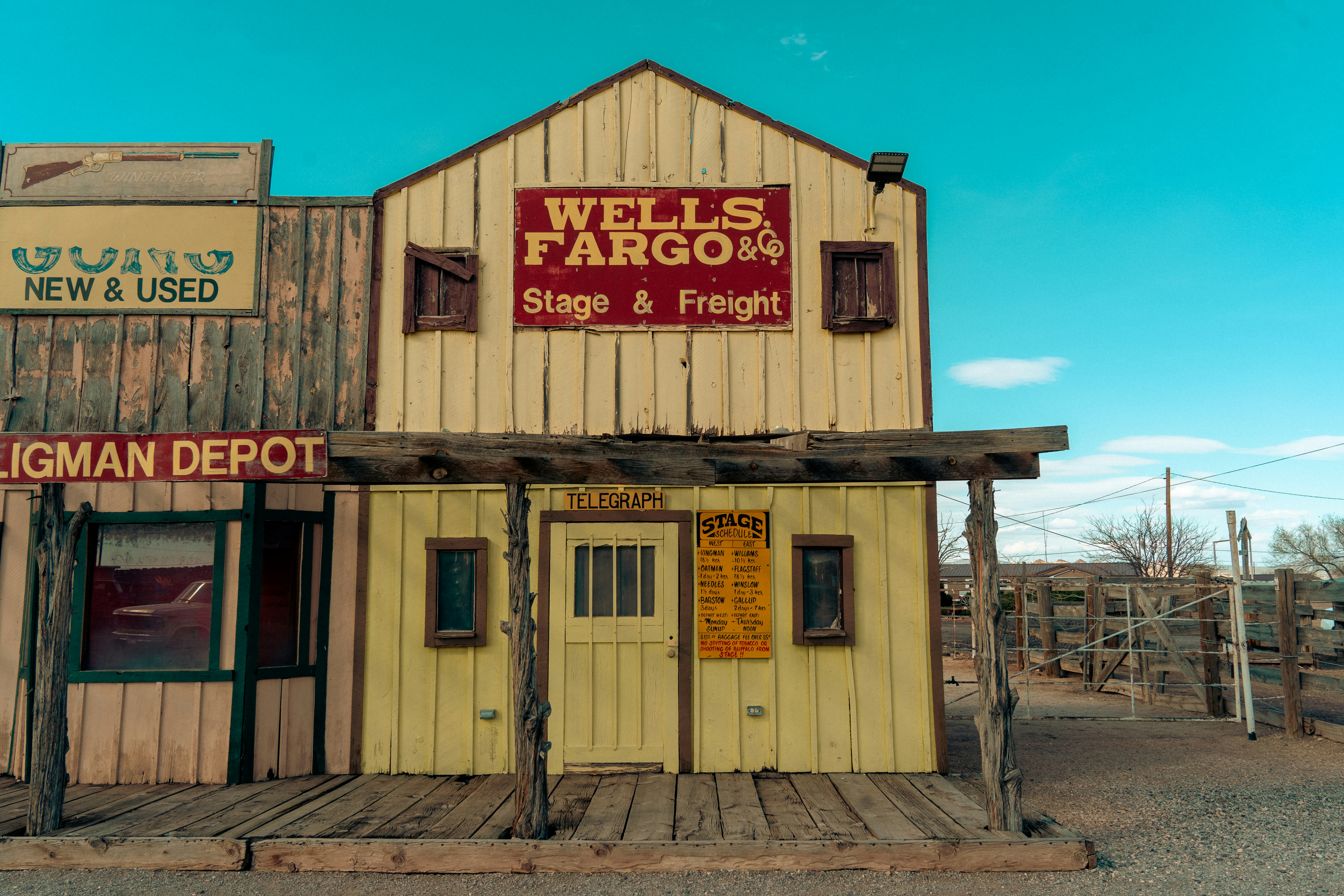 Rustic wooden storefronts with vintage signs under a clear blue sky.