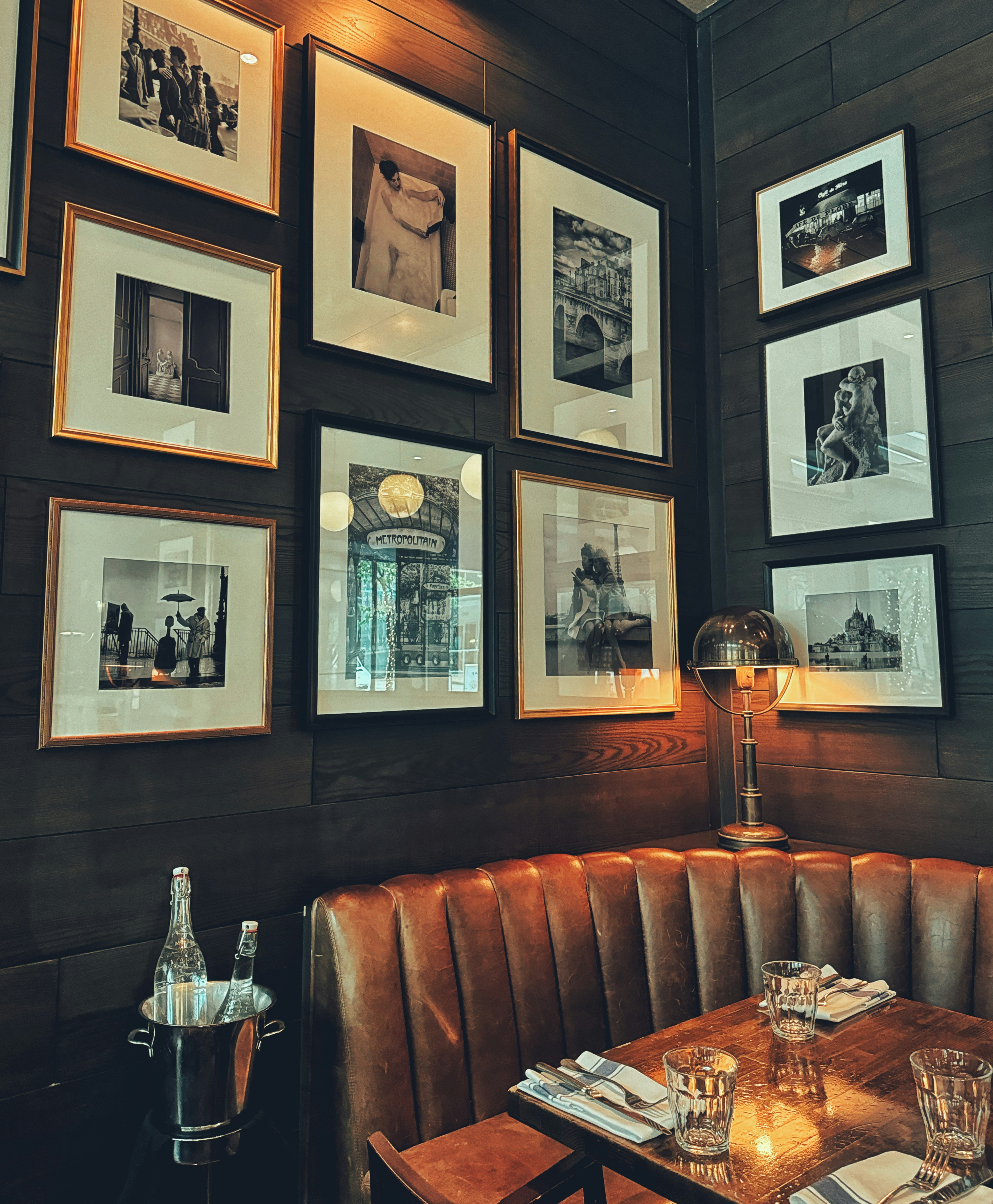 Cozy restaurant nook with framed black-and-white photographs on dark walls and a leather banquette.