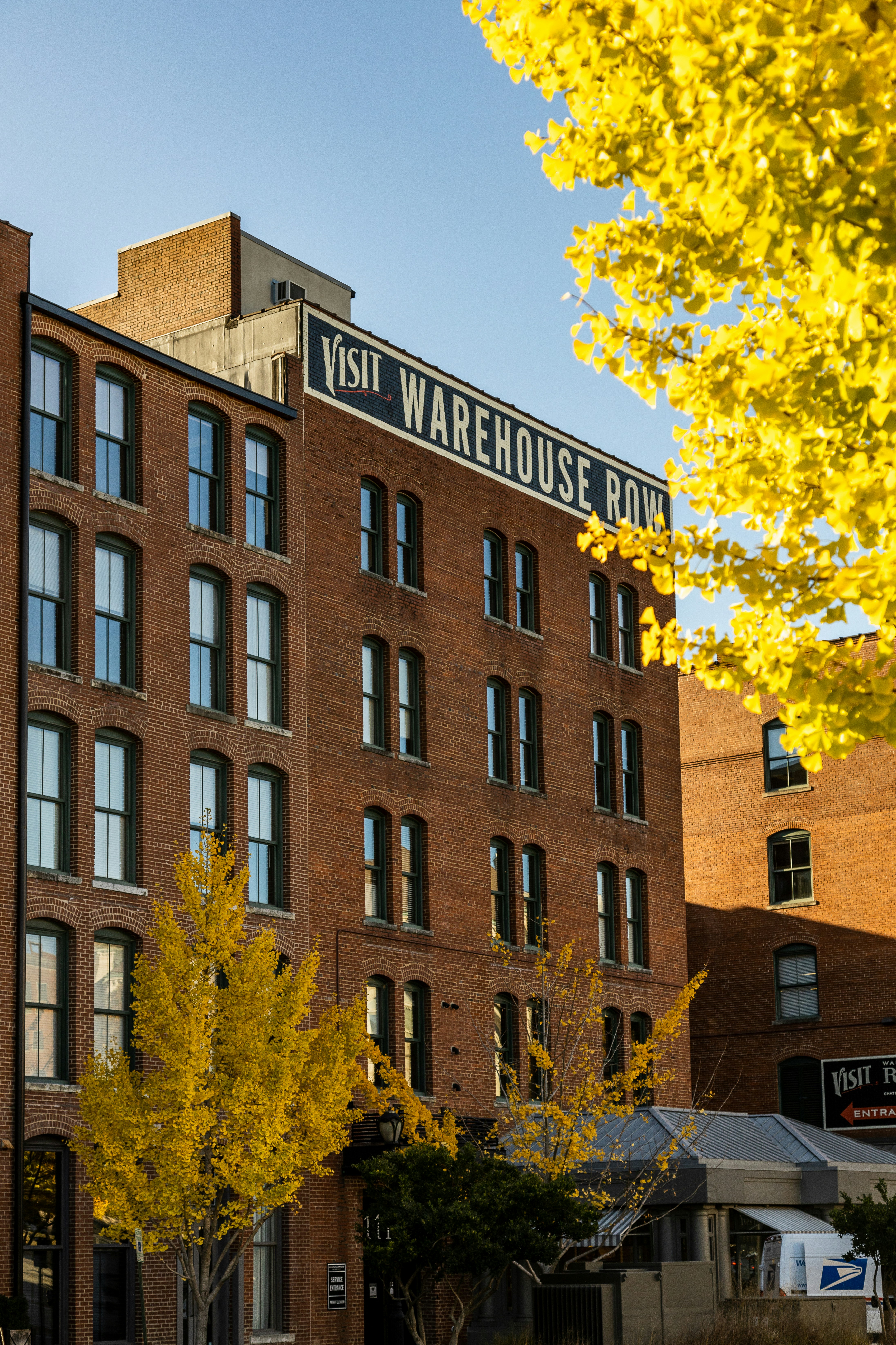 Brick buildings of Warehouse Row with bright yellow autumn foliage under a clear blue sky.