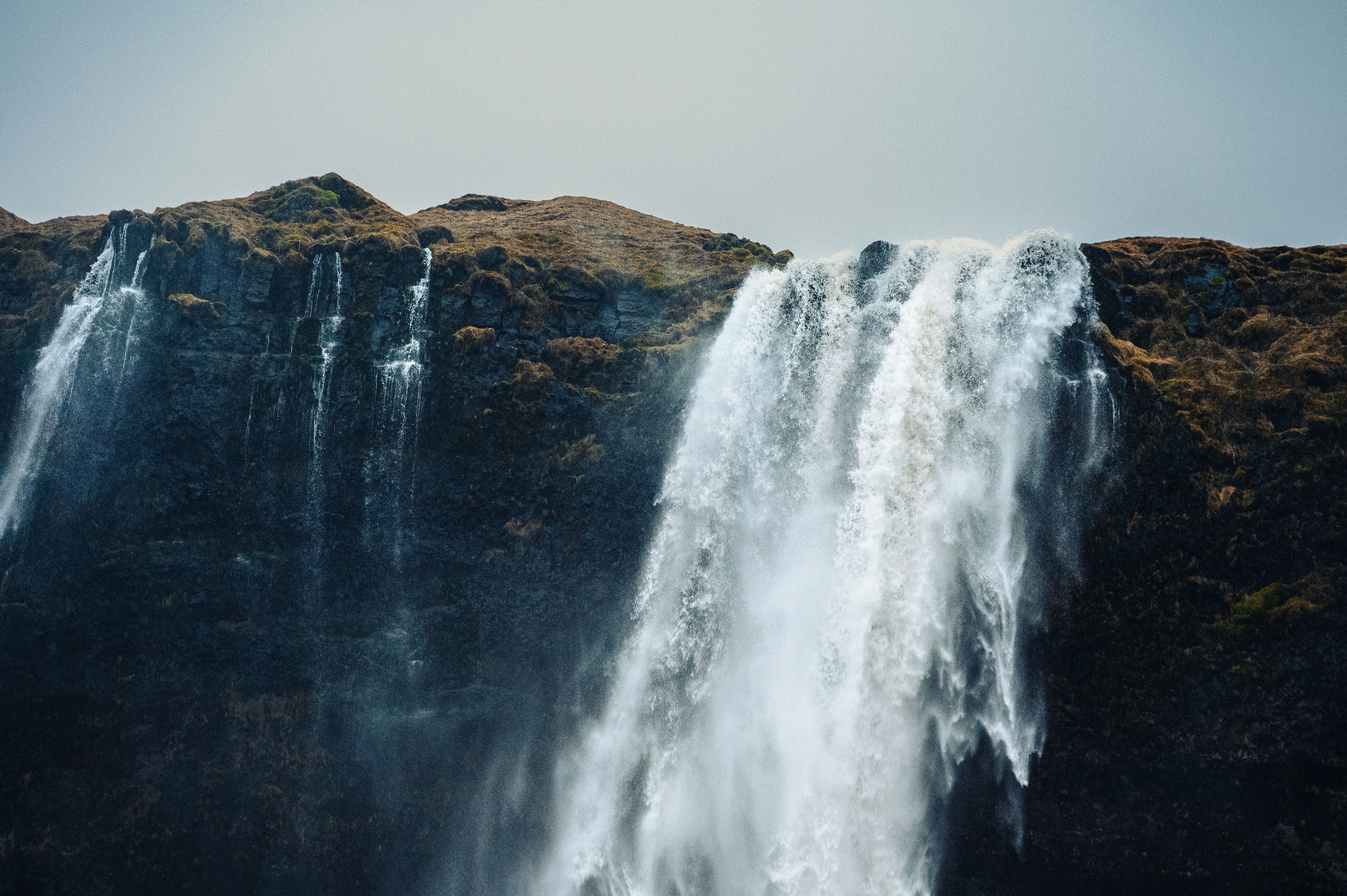 Waterfalls tumbling over rocky cliffs under a clear sky.