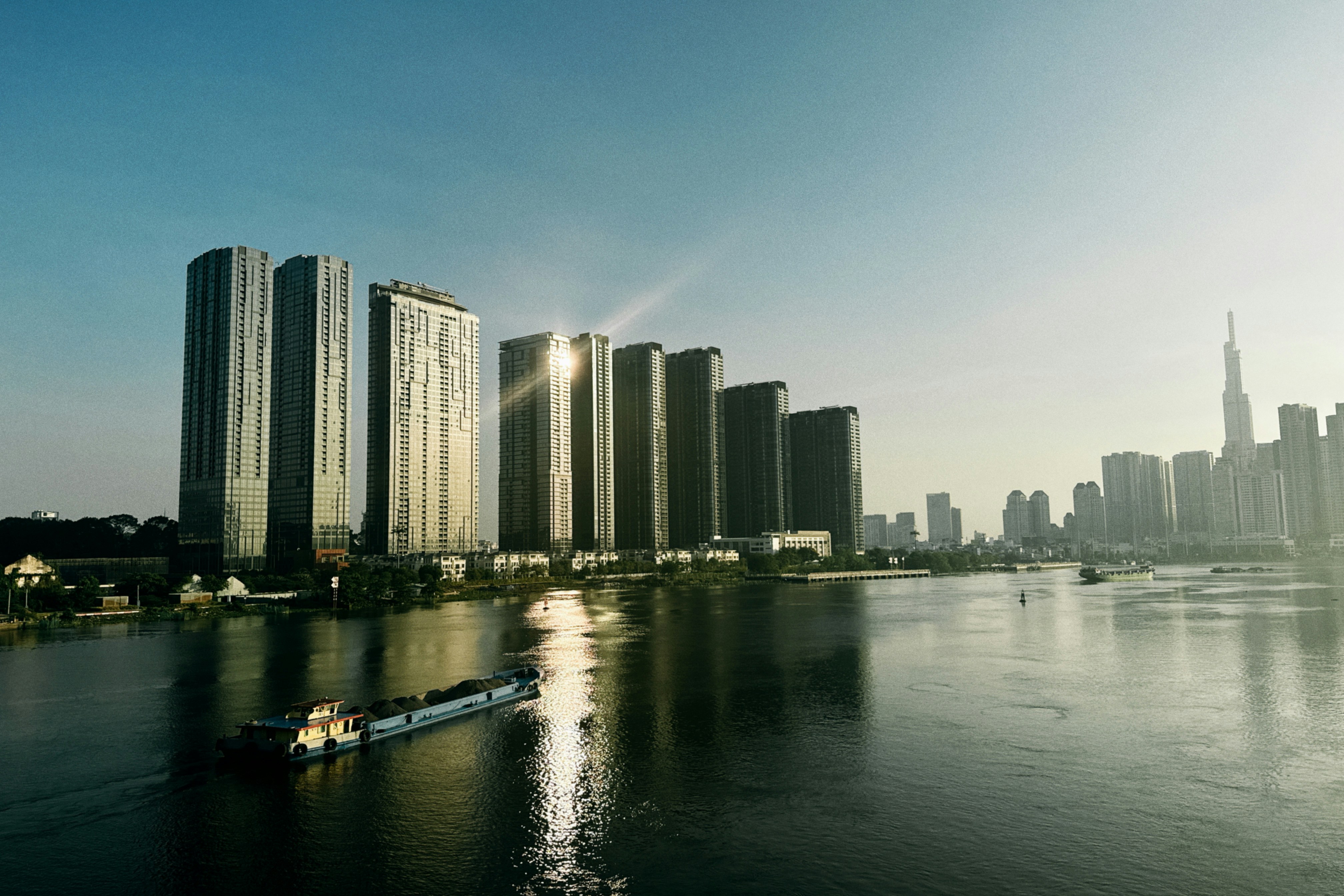 Skyscrapers stand by a river in the city. photo – Free City Image on ...
