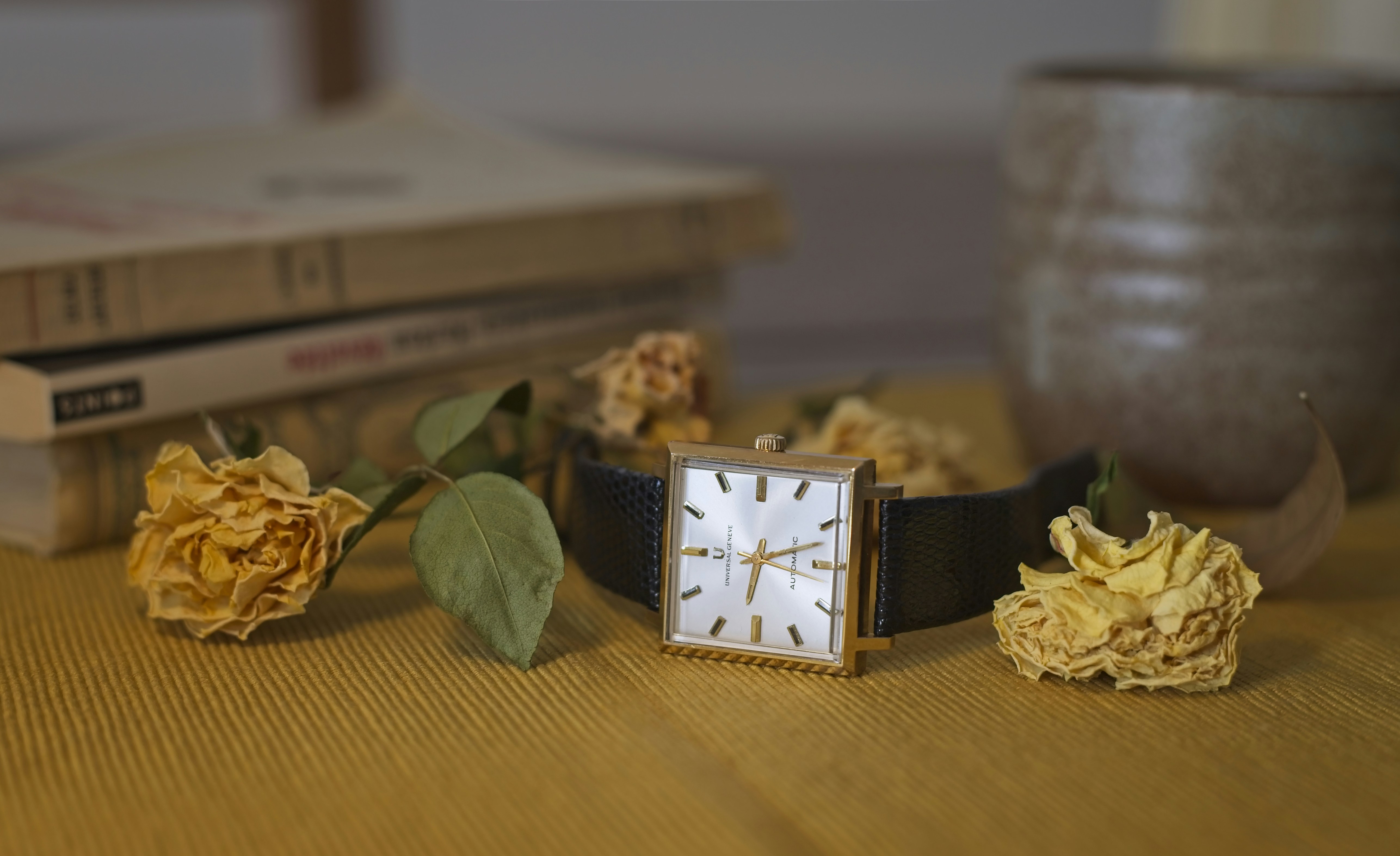 Gold-Framed Square Watch Anchored by Dried Roses on a Warm Wooden Table