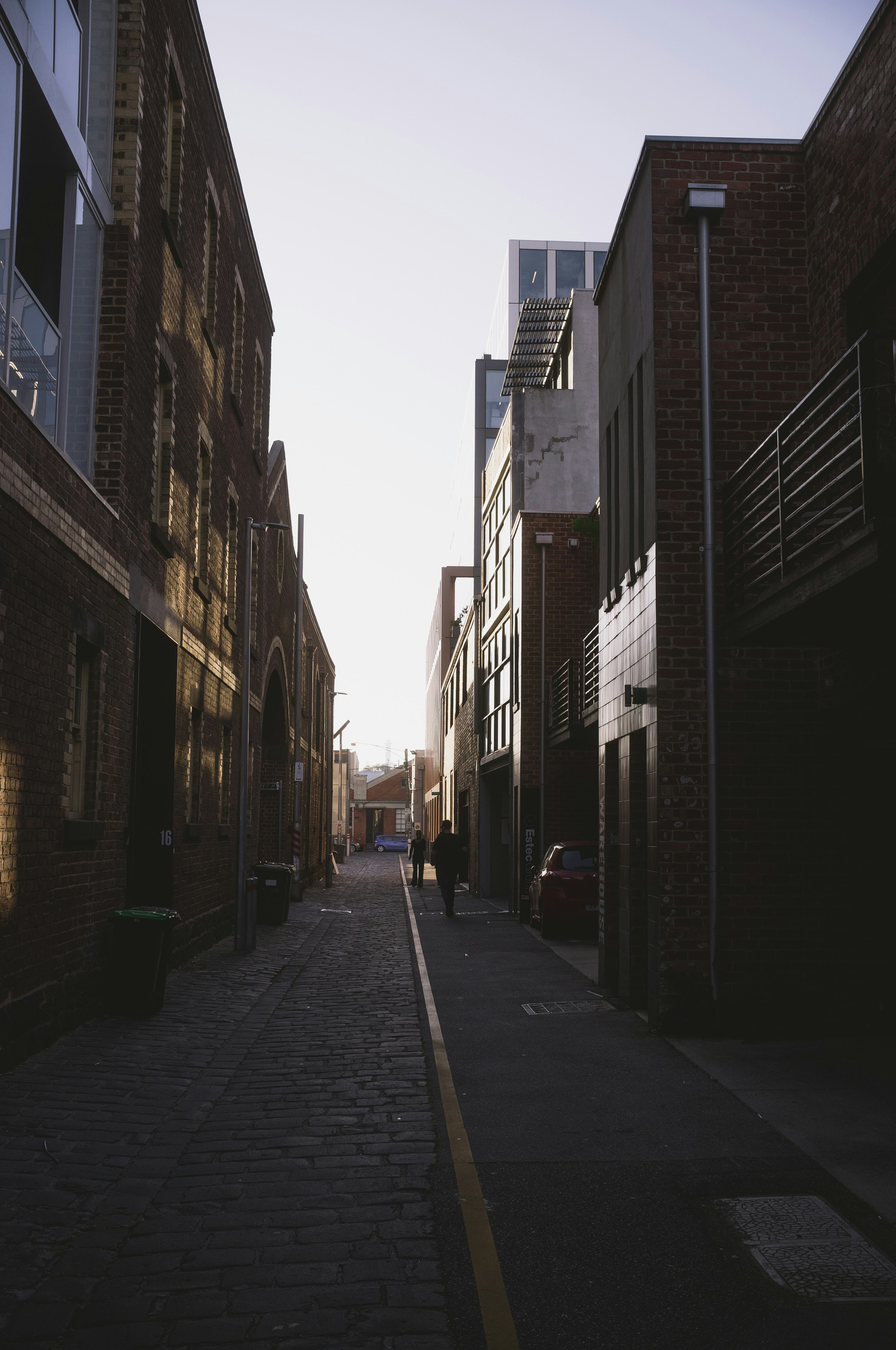 Narrow cobblestone alley flanked by brick buildings under soft evening light.