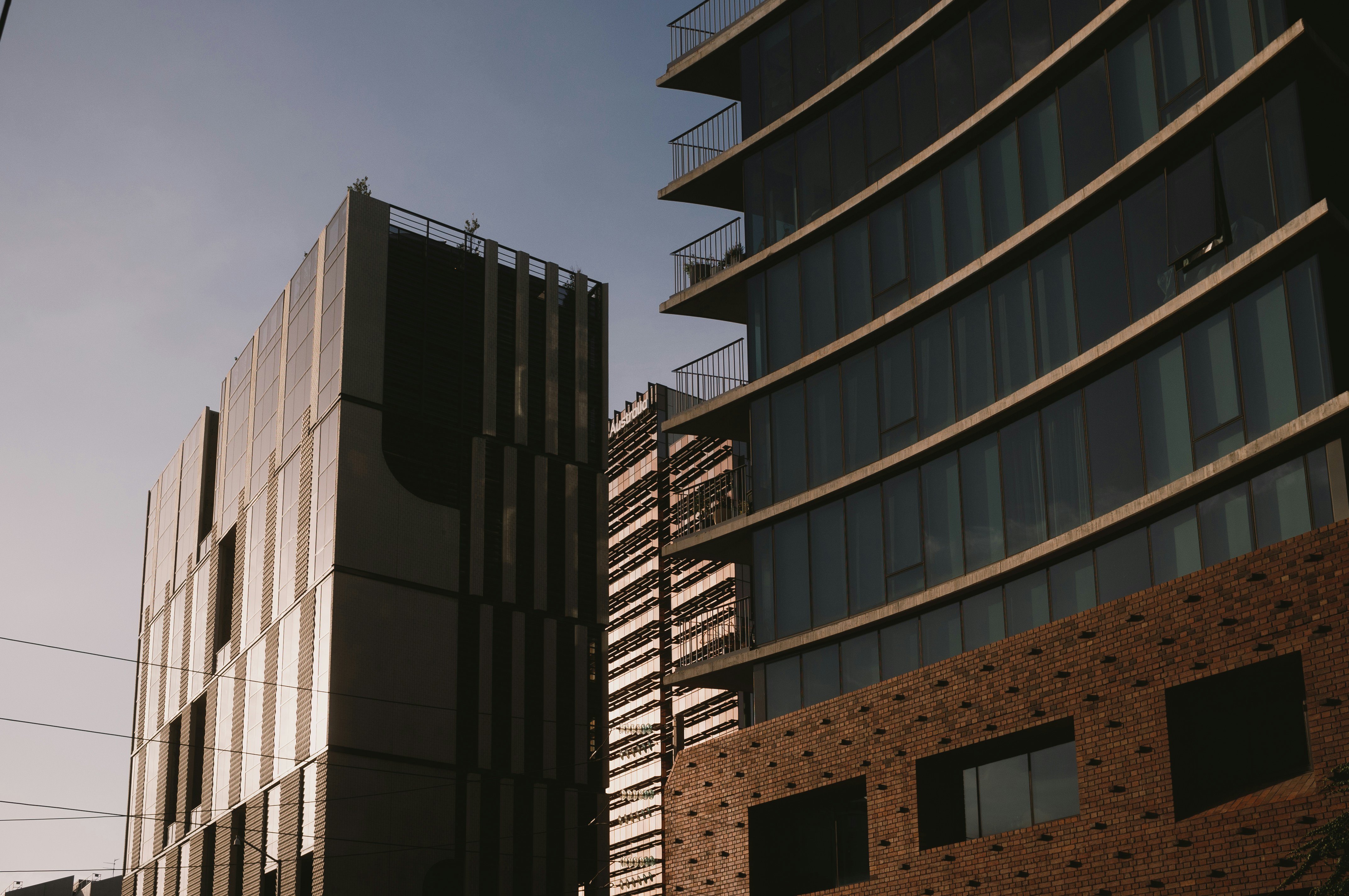 Modern buildings with angular designs and reflective glass under a clear sky.