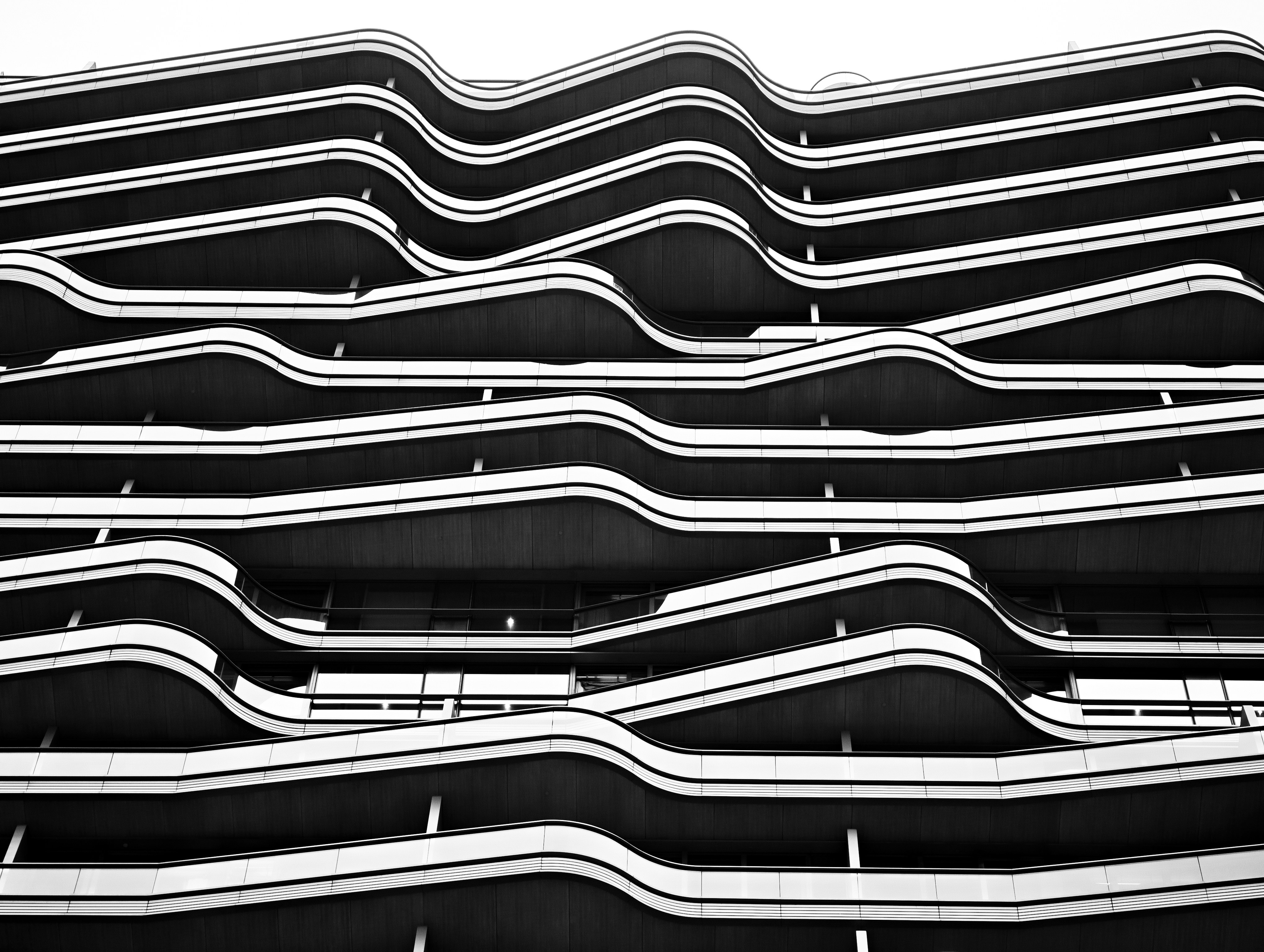 Black-and-white architectural facade with undulating, wave-like lines creating a dynamic modern aesthetic.