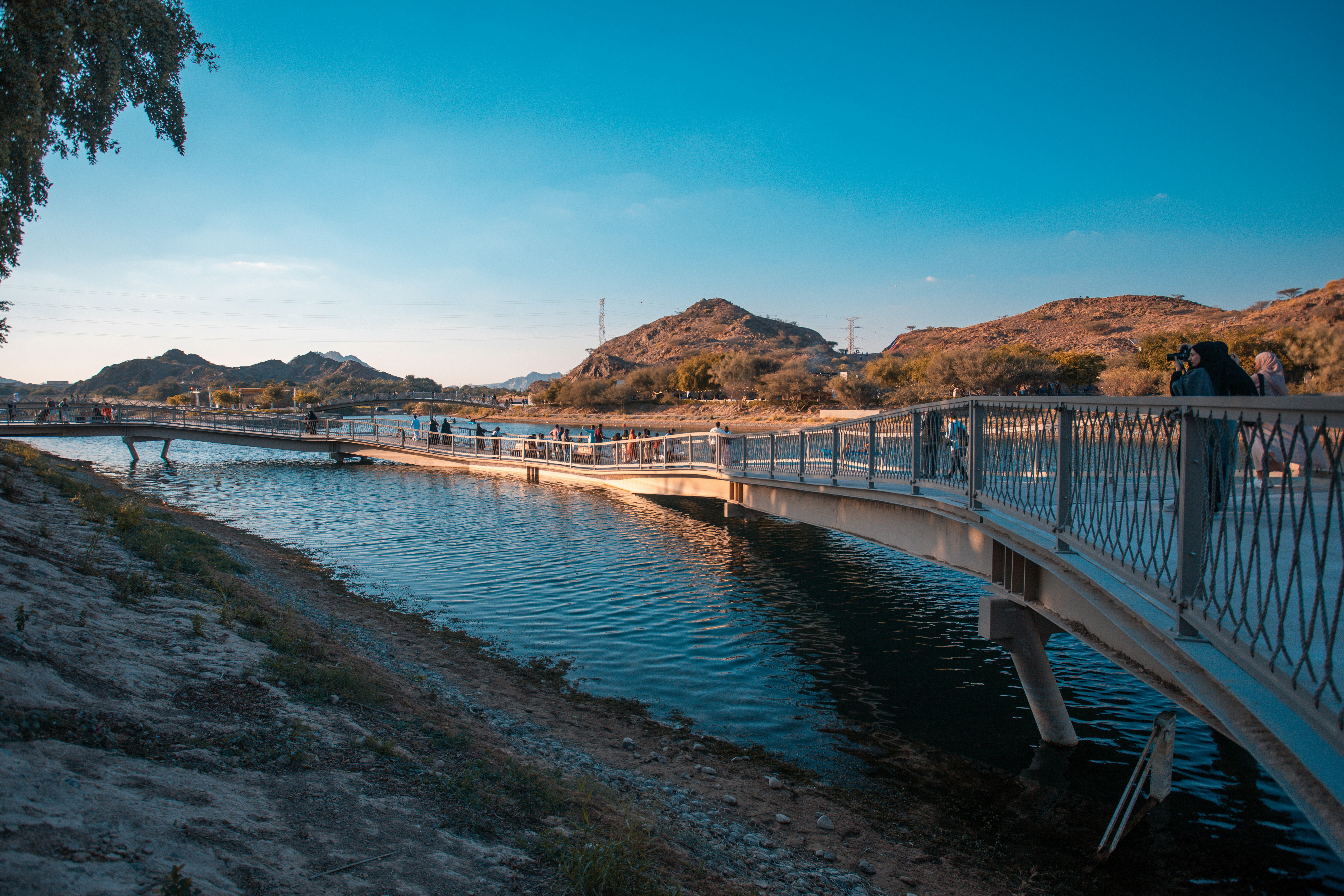 A bridge stretches over water toward a mountain. photo – Free Human ...