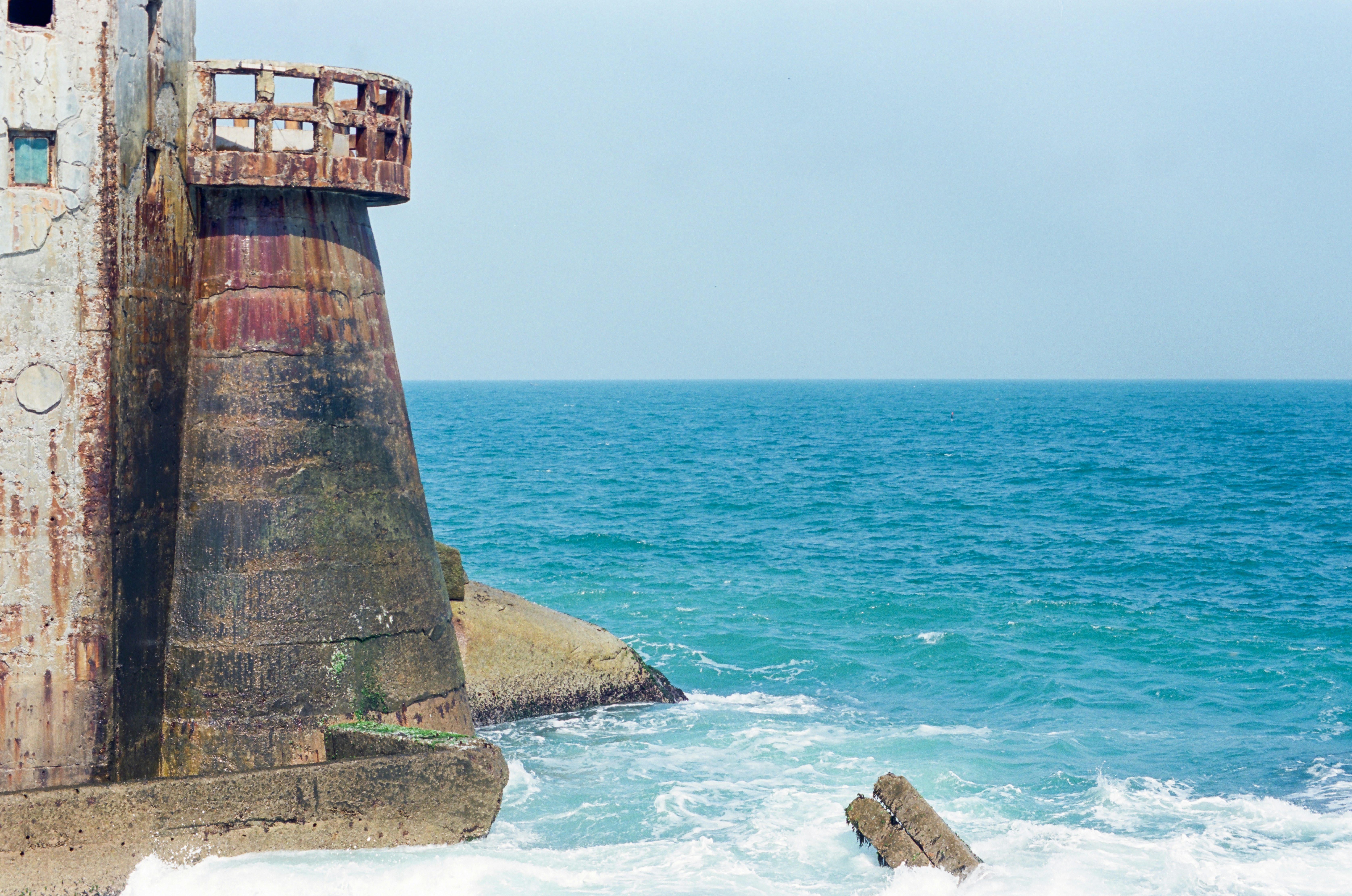 A rusty tower stands over the wavy ocean. photo – Free Beach Image on ...