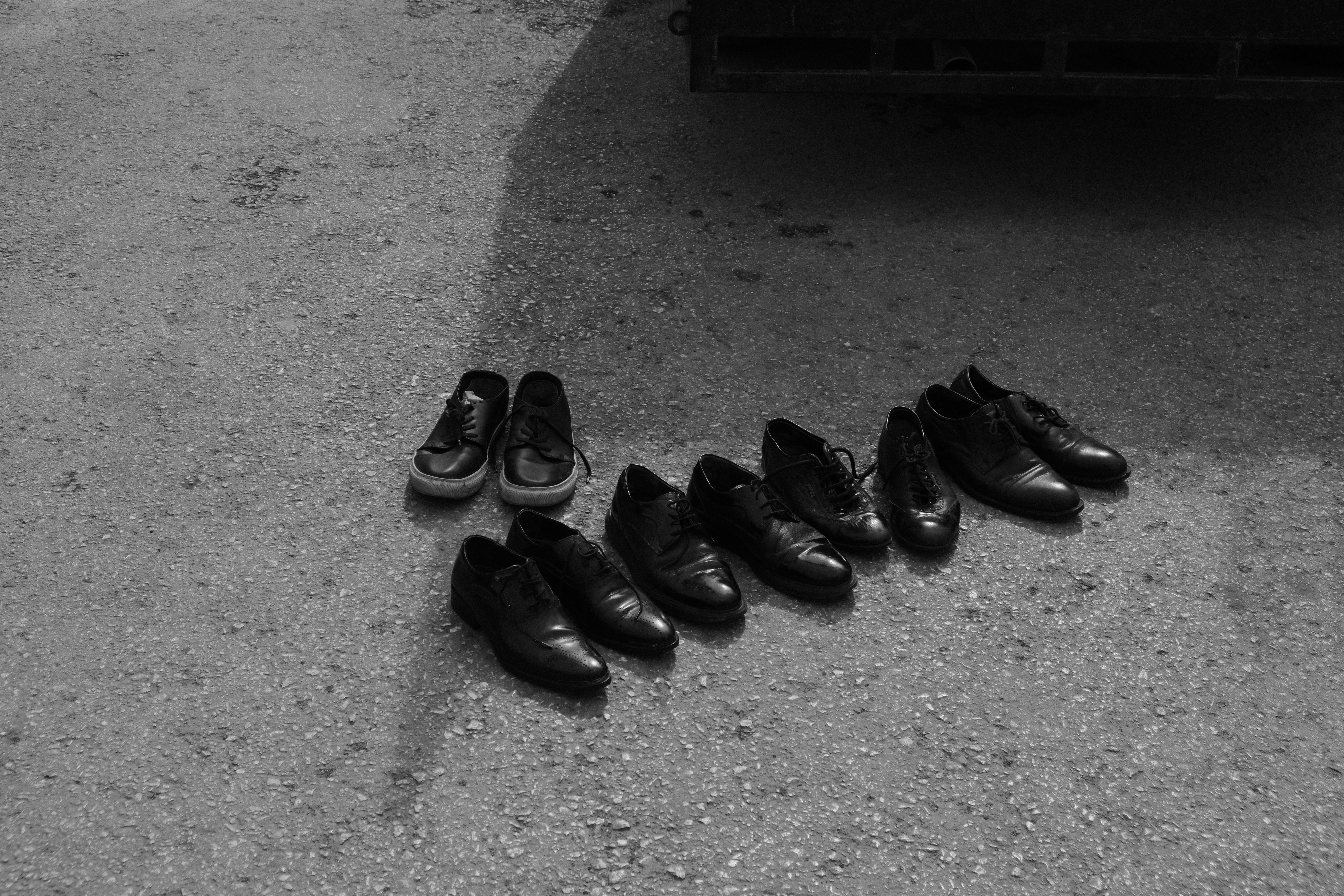 A collection of black shoes arranged on a textured surface, showcasing various styles and sizes. The contrast highlights their unique shapes and designs.