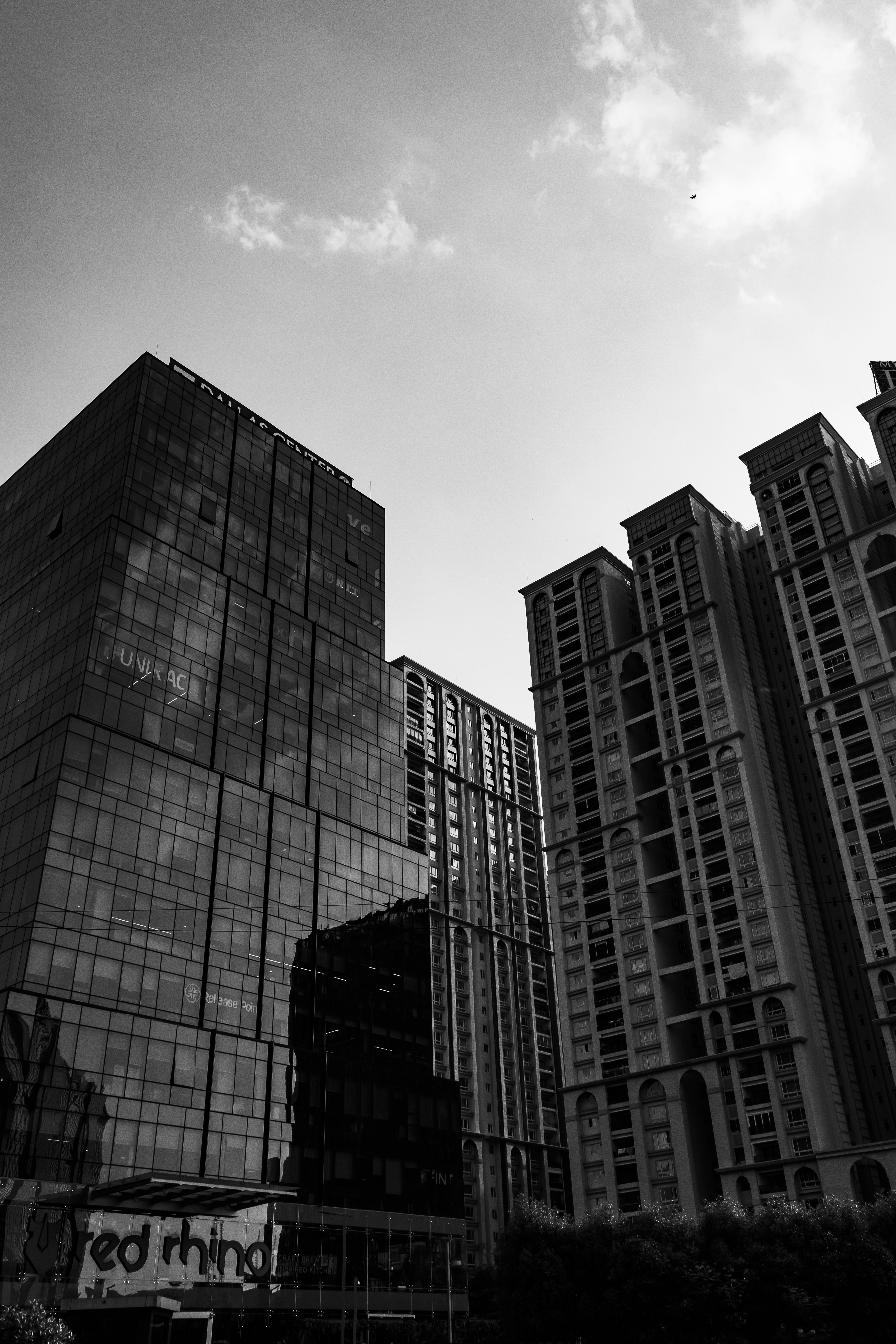 High-rise buildings captured in black and white under a partly cloudy sky.