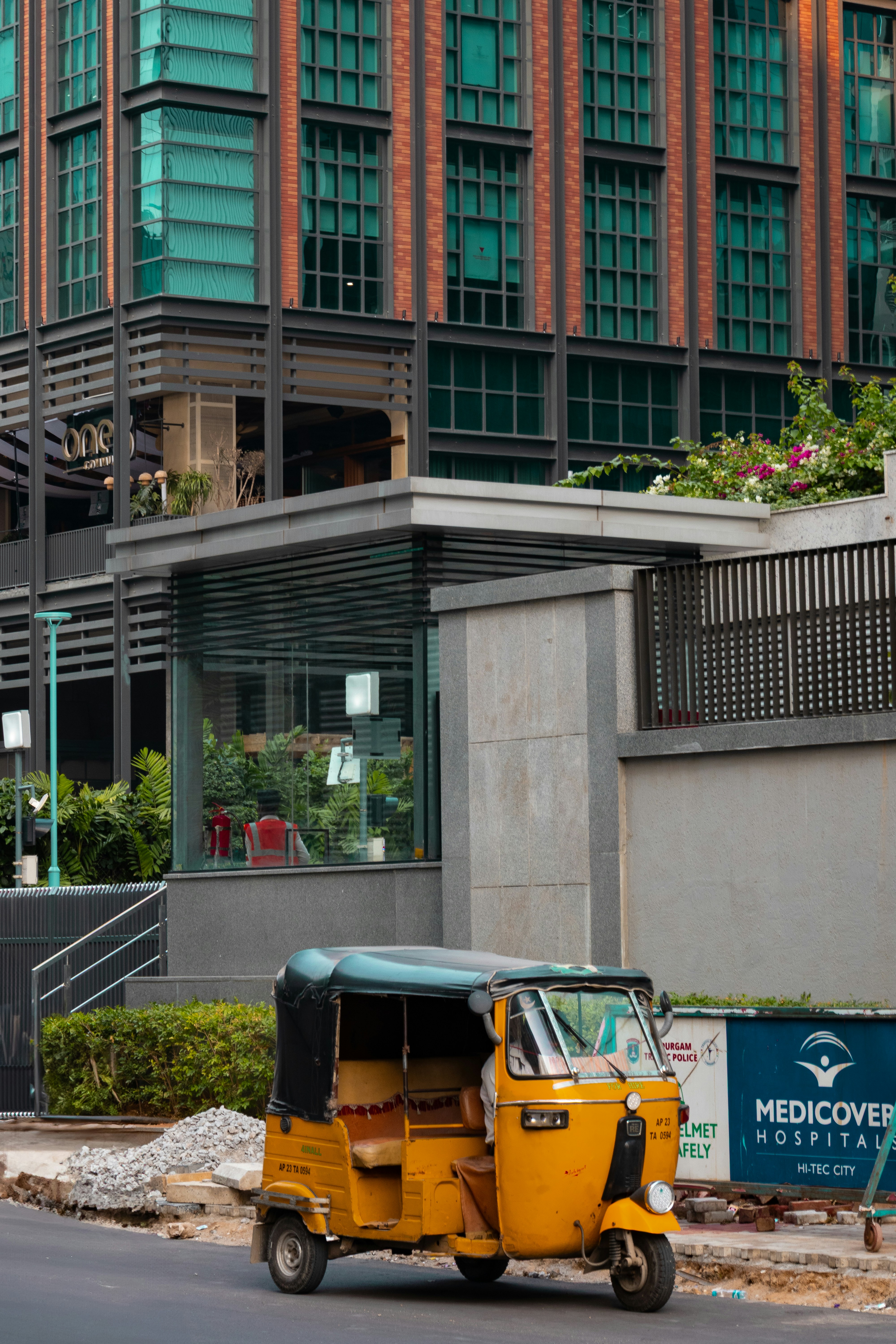 A yellow tuk-tuk parked in front of a building.
