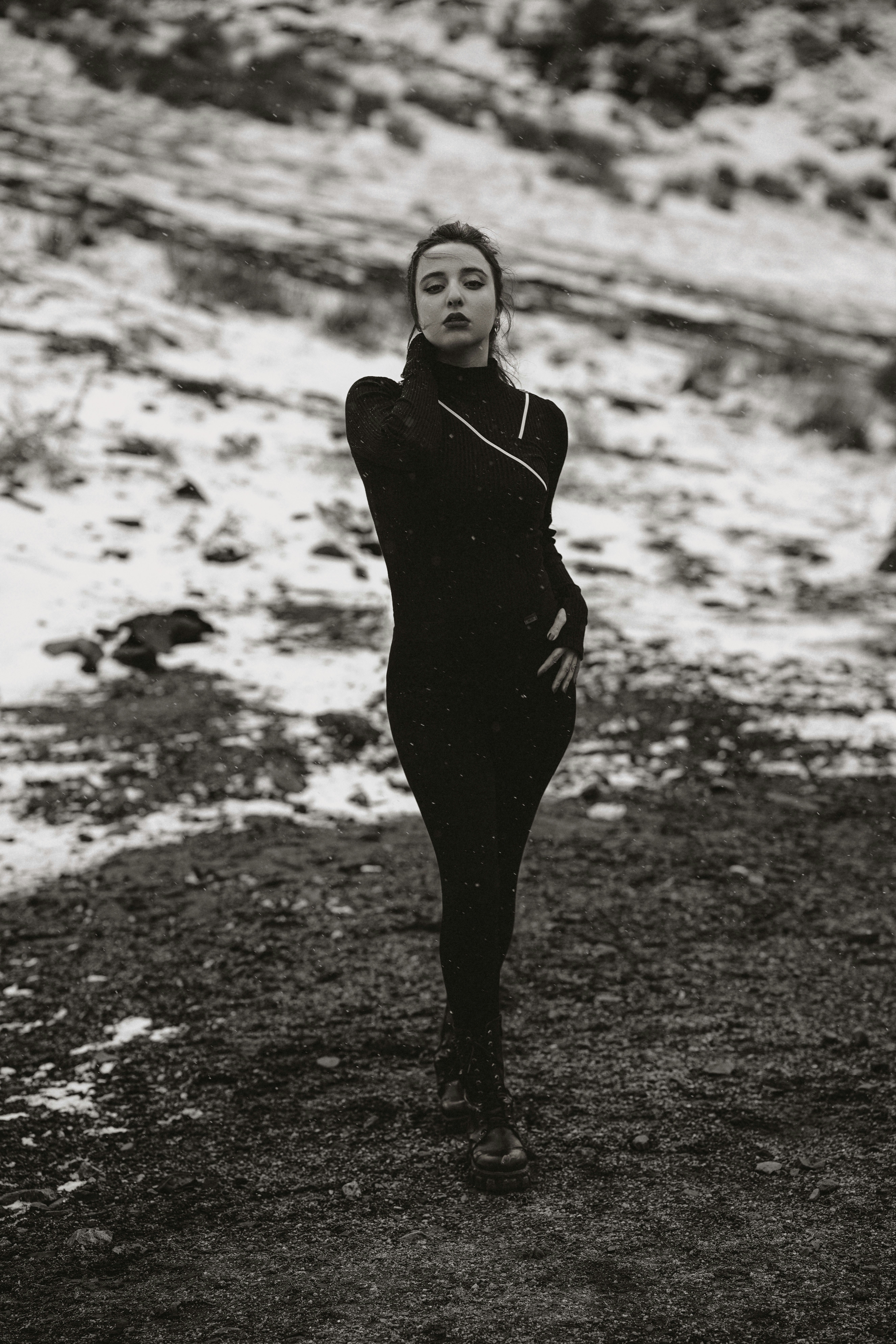 Person in dark clothing stands confidently on a snow-dusted landscape.