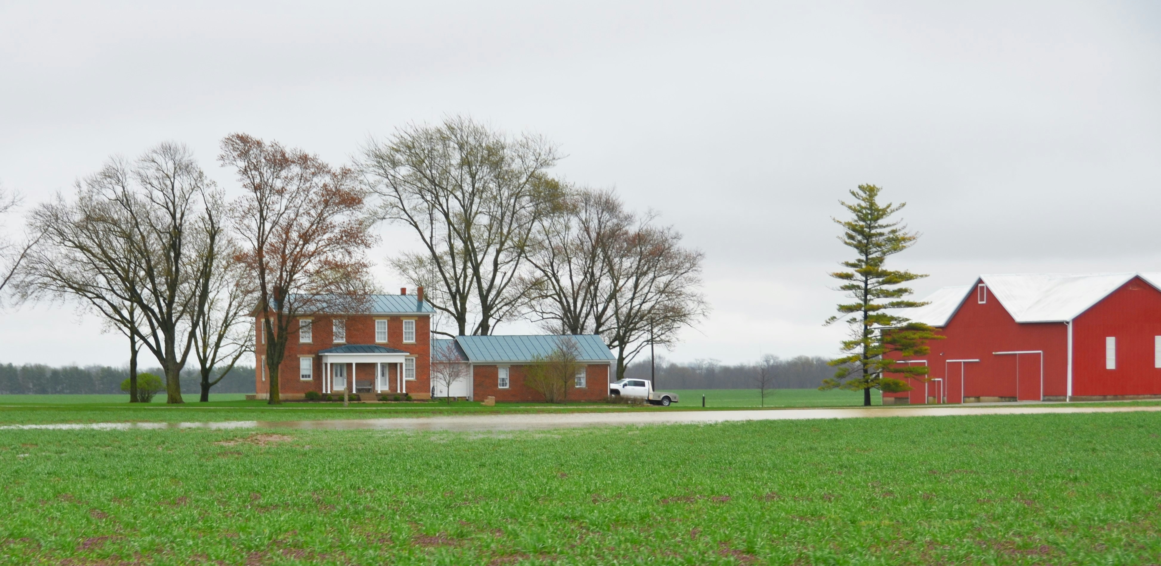 A farmhouse and barn in a green field. photo – Free House Image on Unsplash