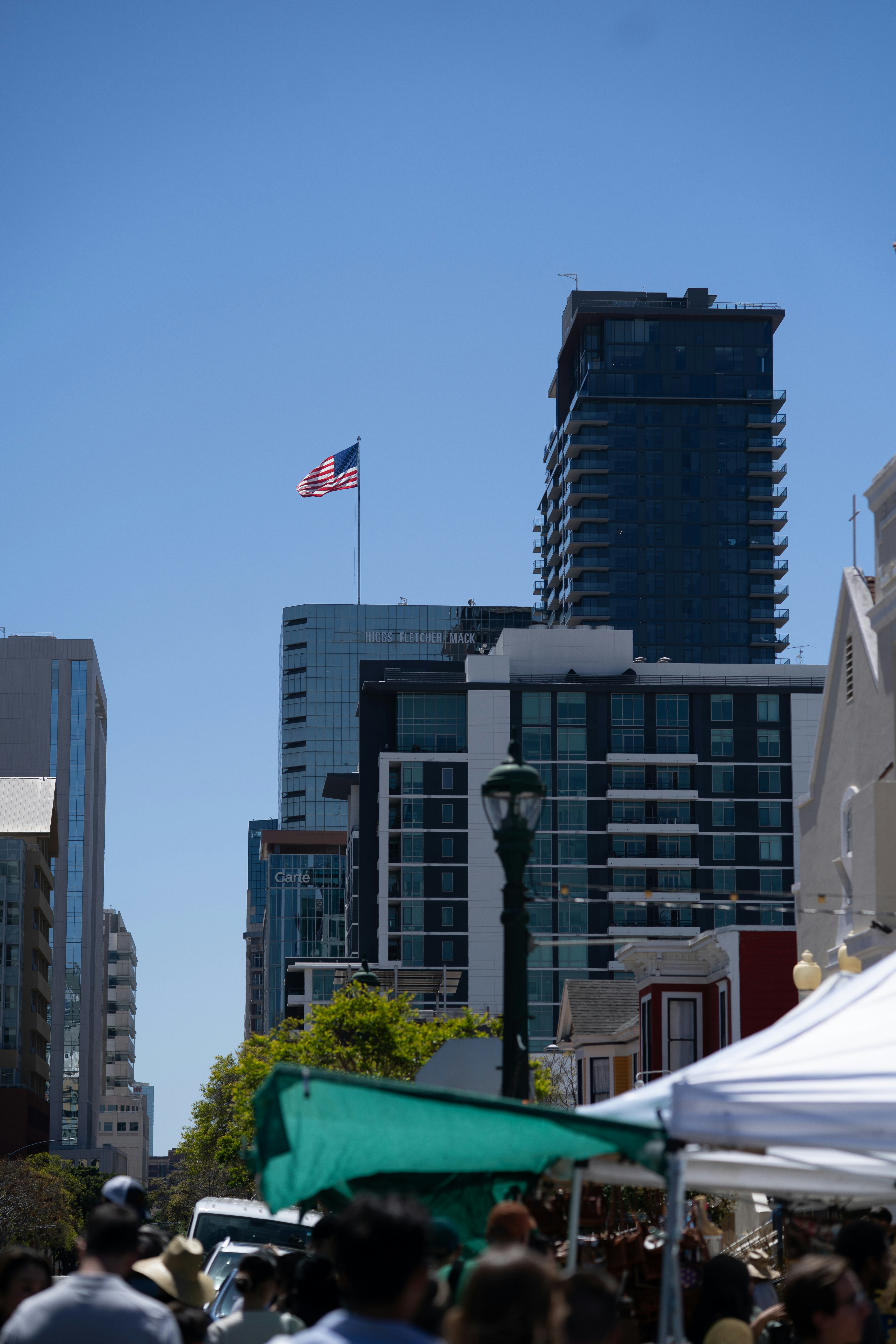 City street market with a backdrop of modern high-rise buildings and a waving American flag.