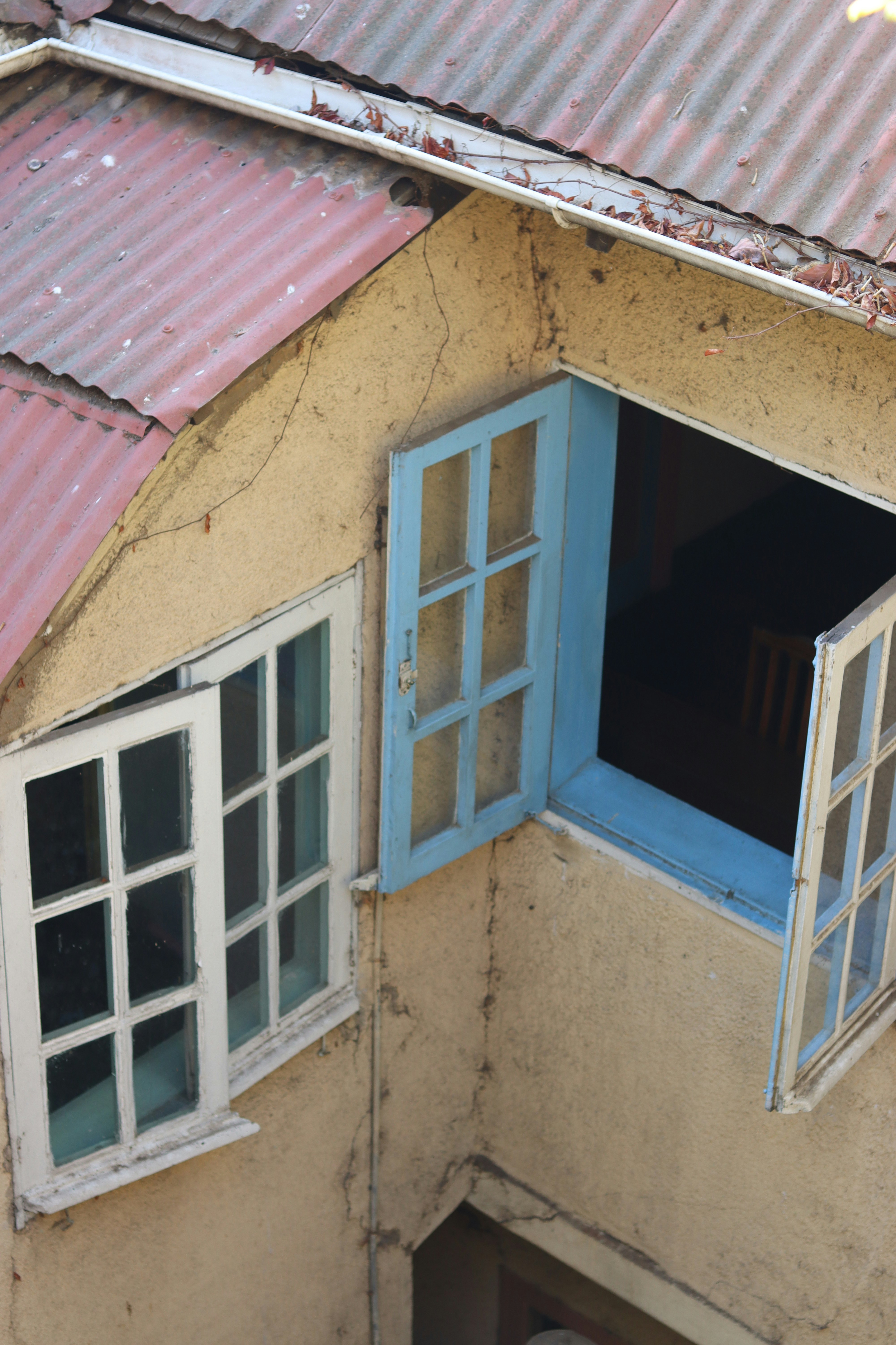 Blue-framed window on a sun-worn adobe corner