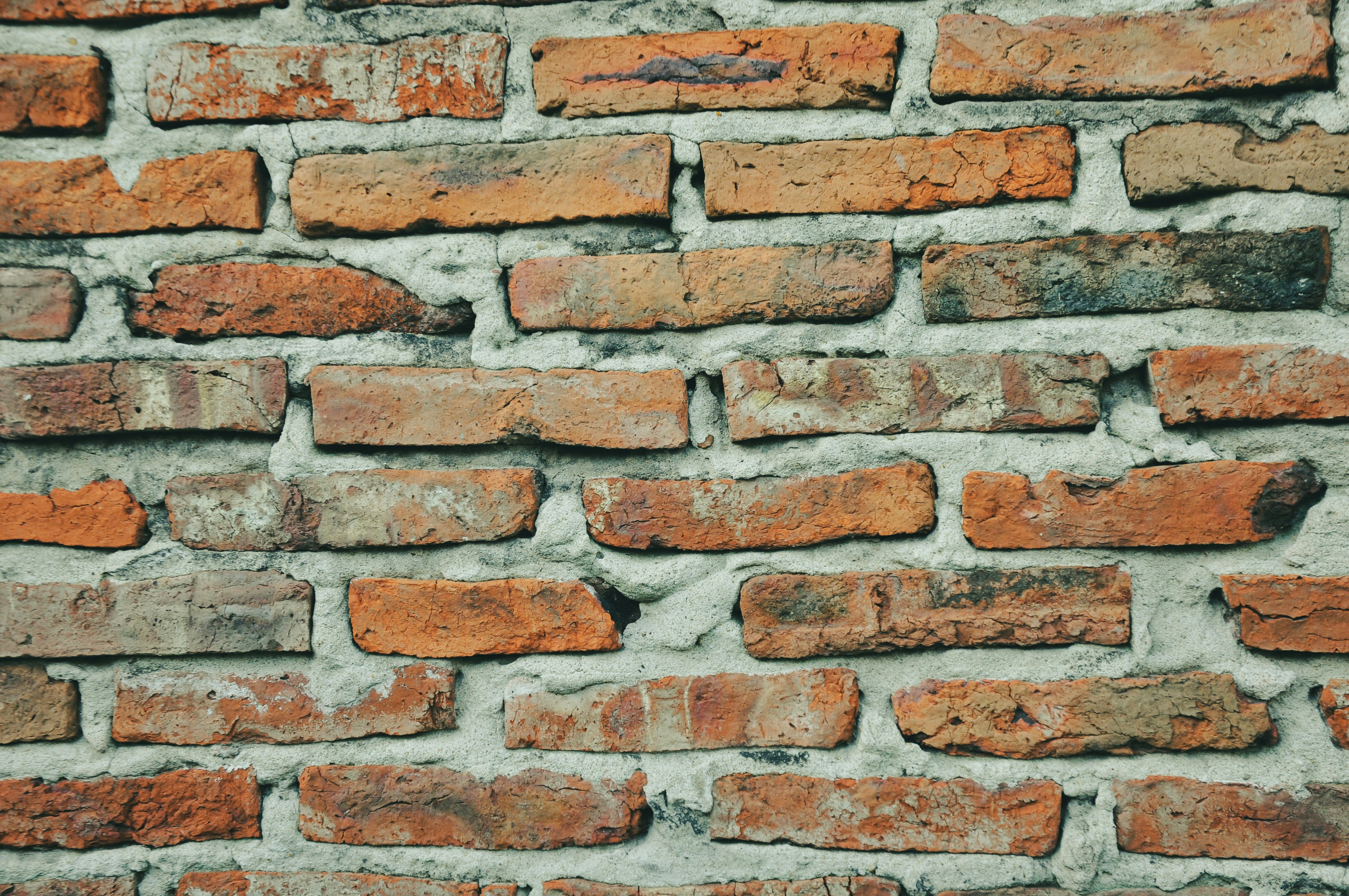 Close-up of a rustic red brick wall with uneven cement joints and rough texture.
