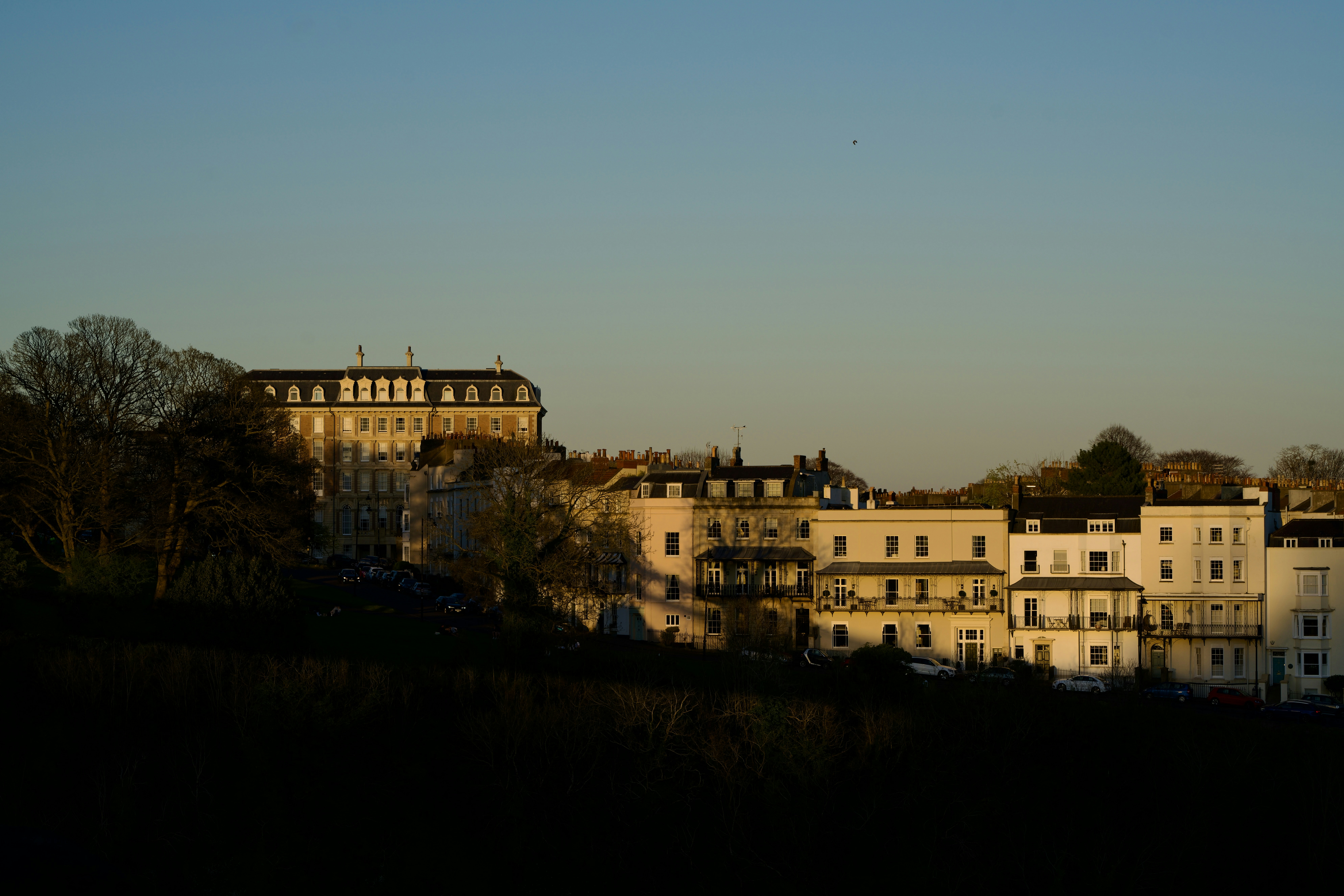 Sunset casts warm light on historic buildings with a clear blue sky overhead.