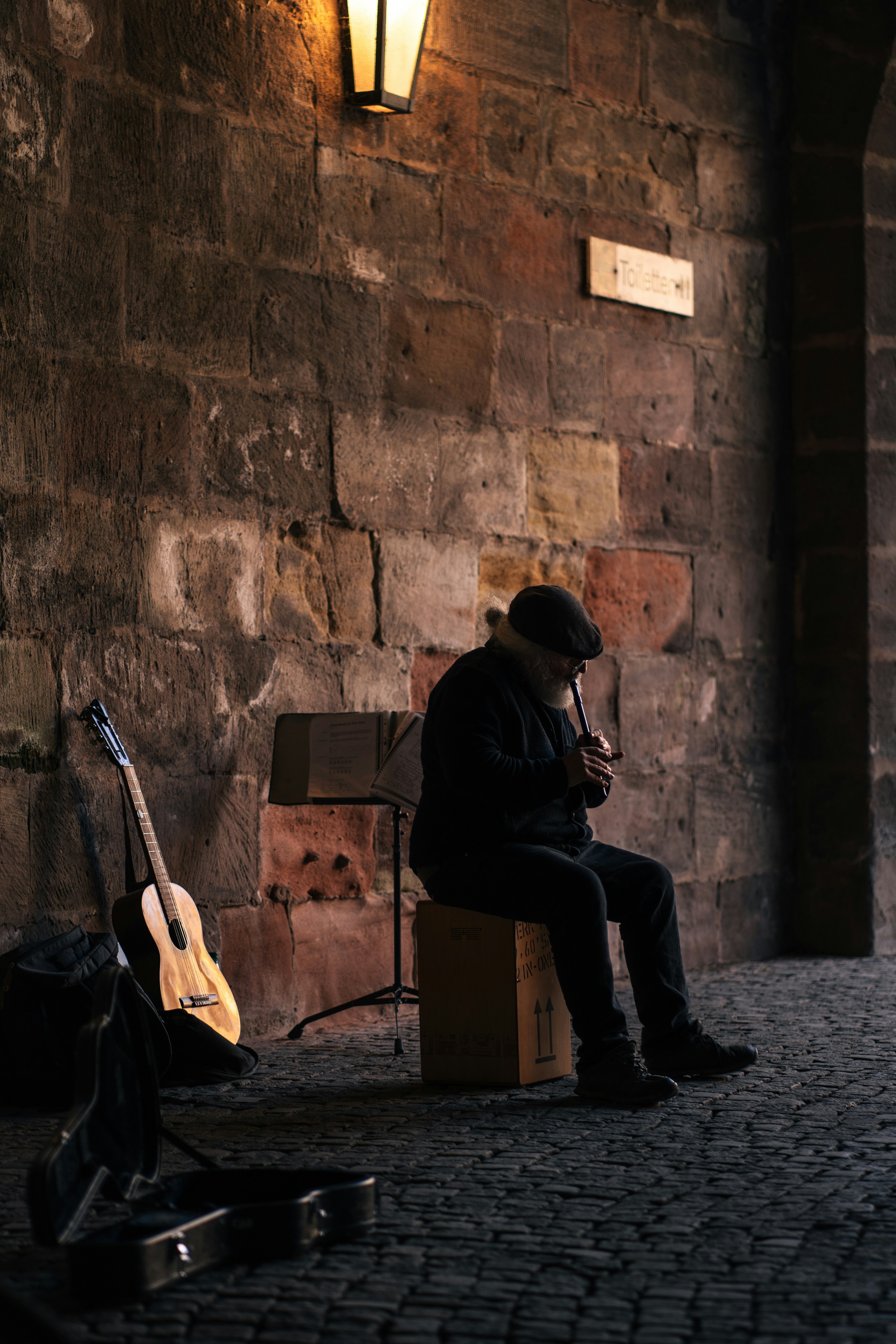 A street musician plays his instrument by a wall. photo – Free Man ...