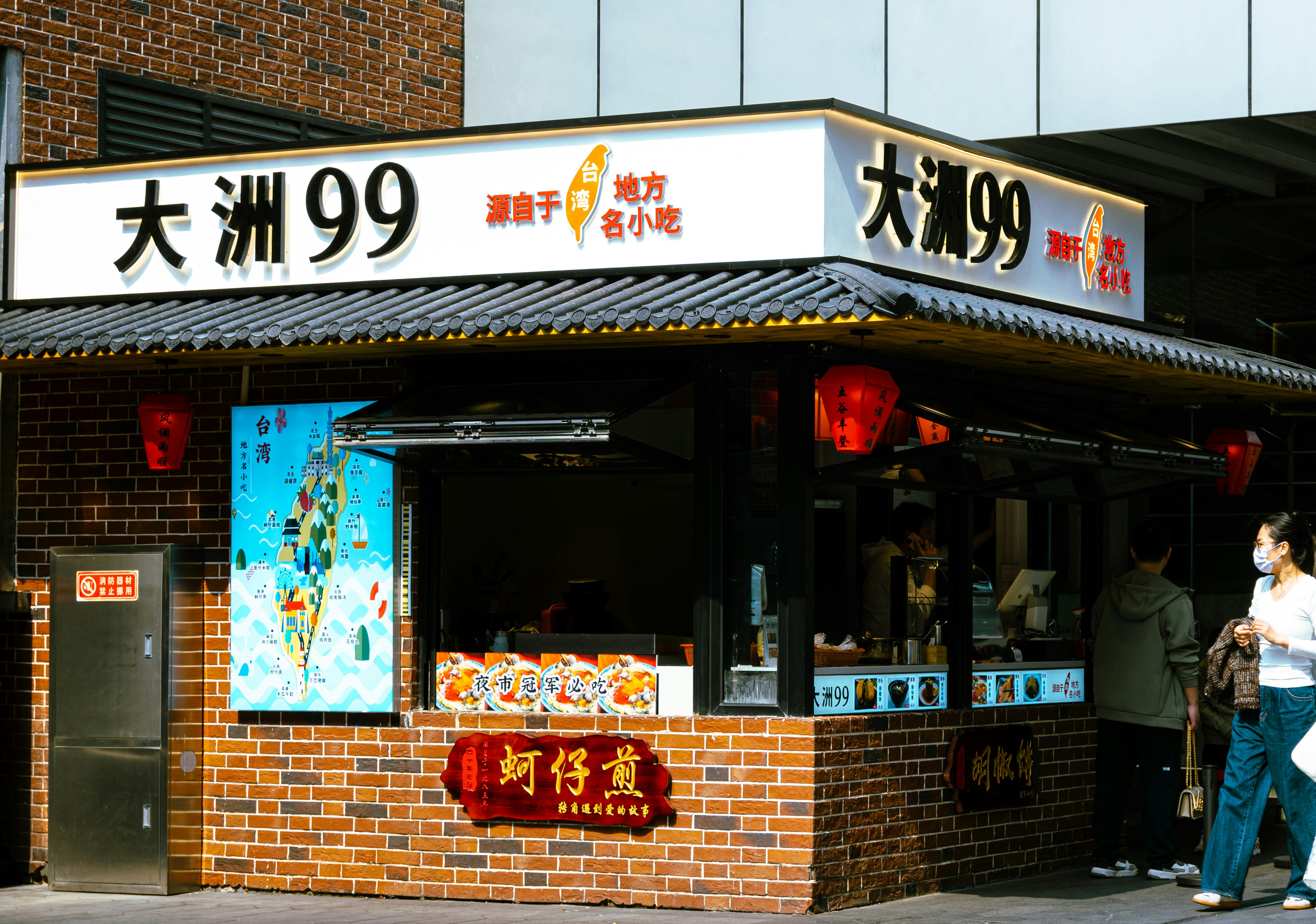Small brick food stall adorned with red lanterns and vibrant signage.