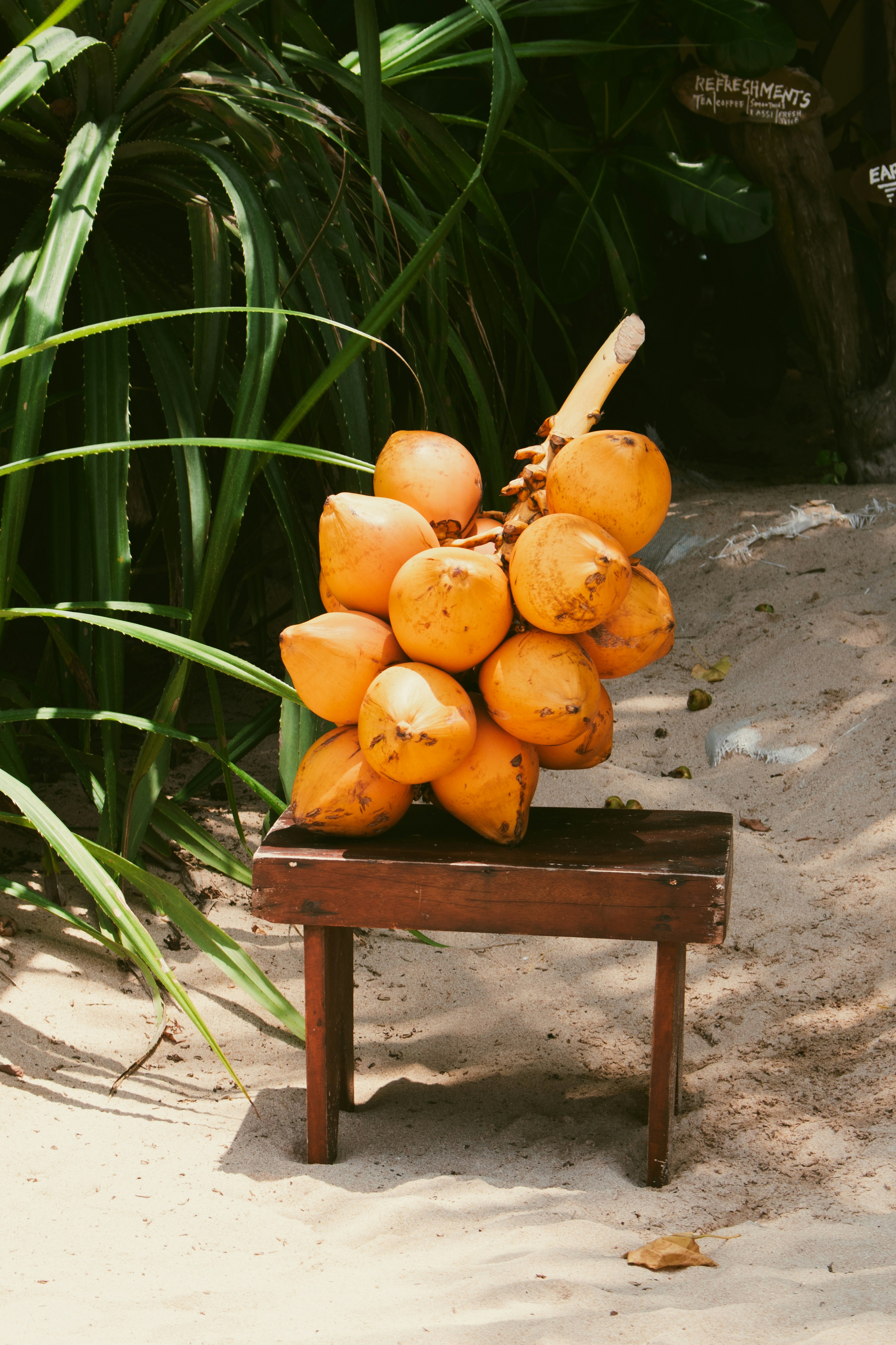 A bunch of orange coconuts sits on a small table. photo – Free Fruit ...