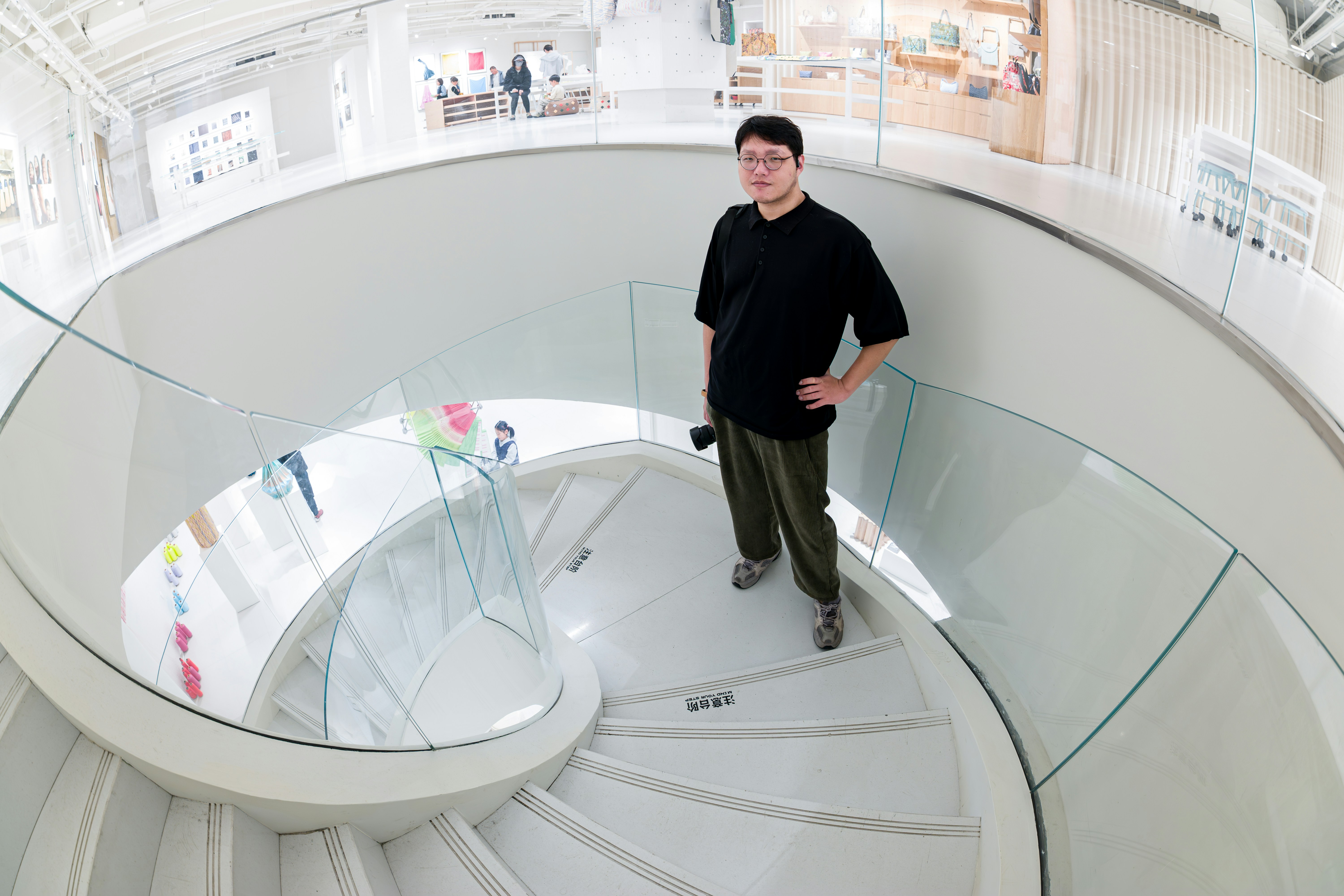 Vertical hush of the atrium: a lone observer at the spiral staircase