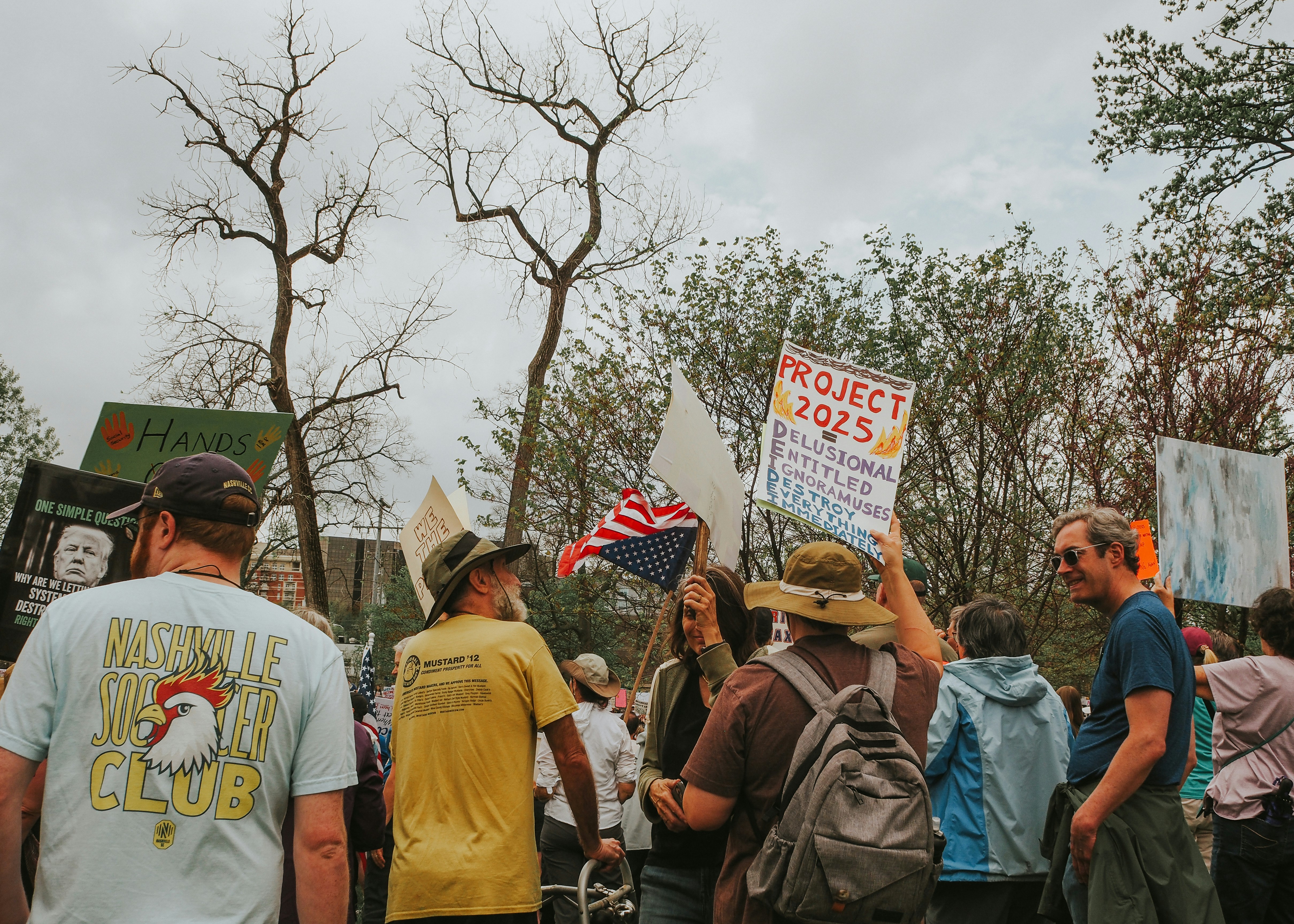 Protesters march with signs and an american flag. photo – Free Man ...