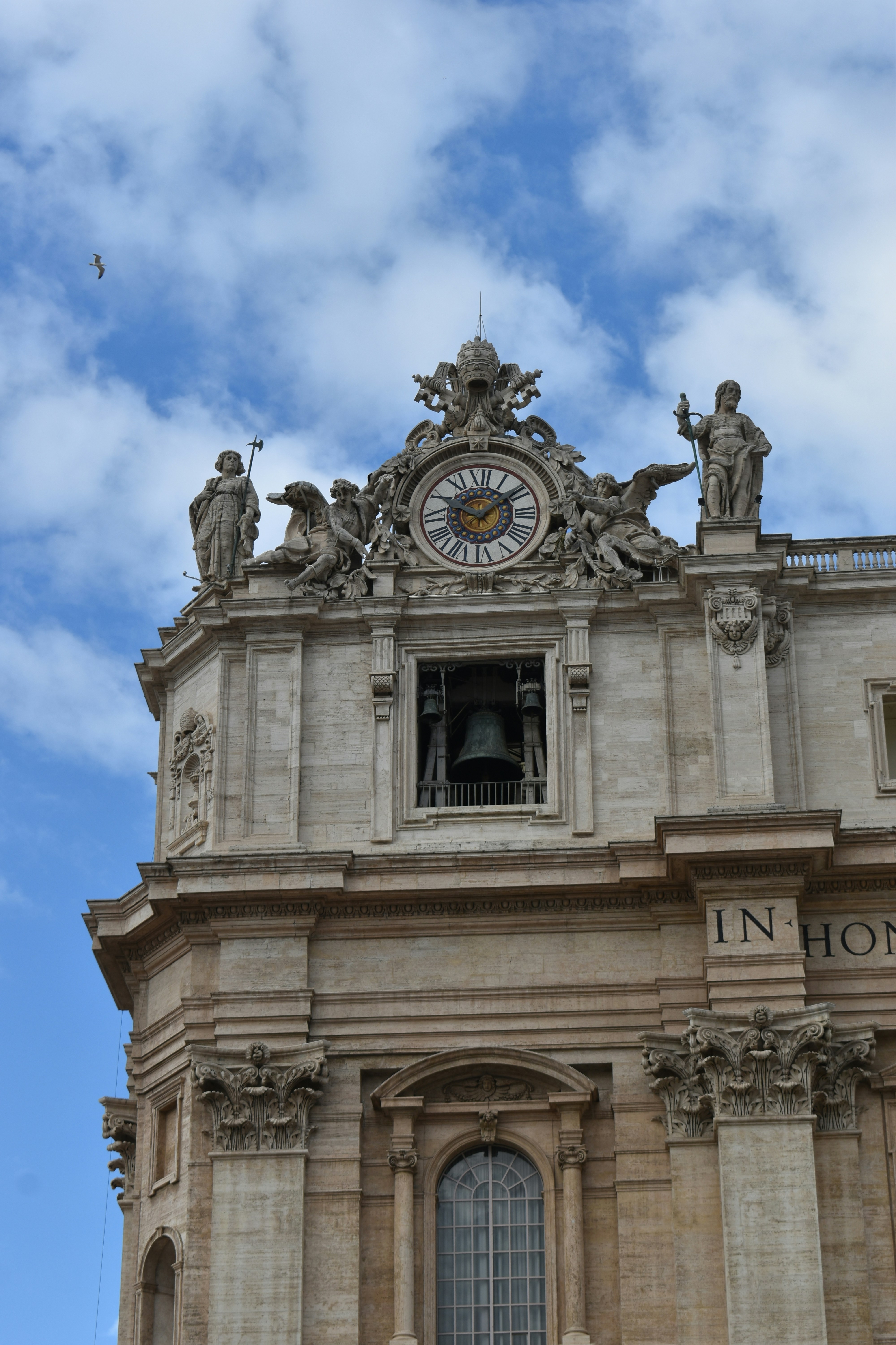 Ornate clock tower with statues against a partly cloudy sky.