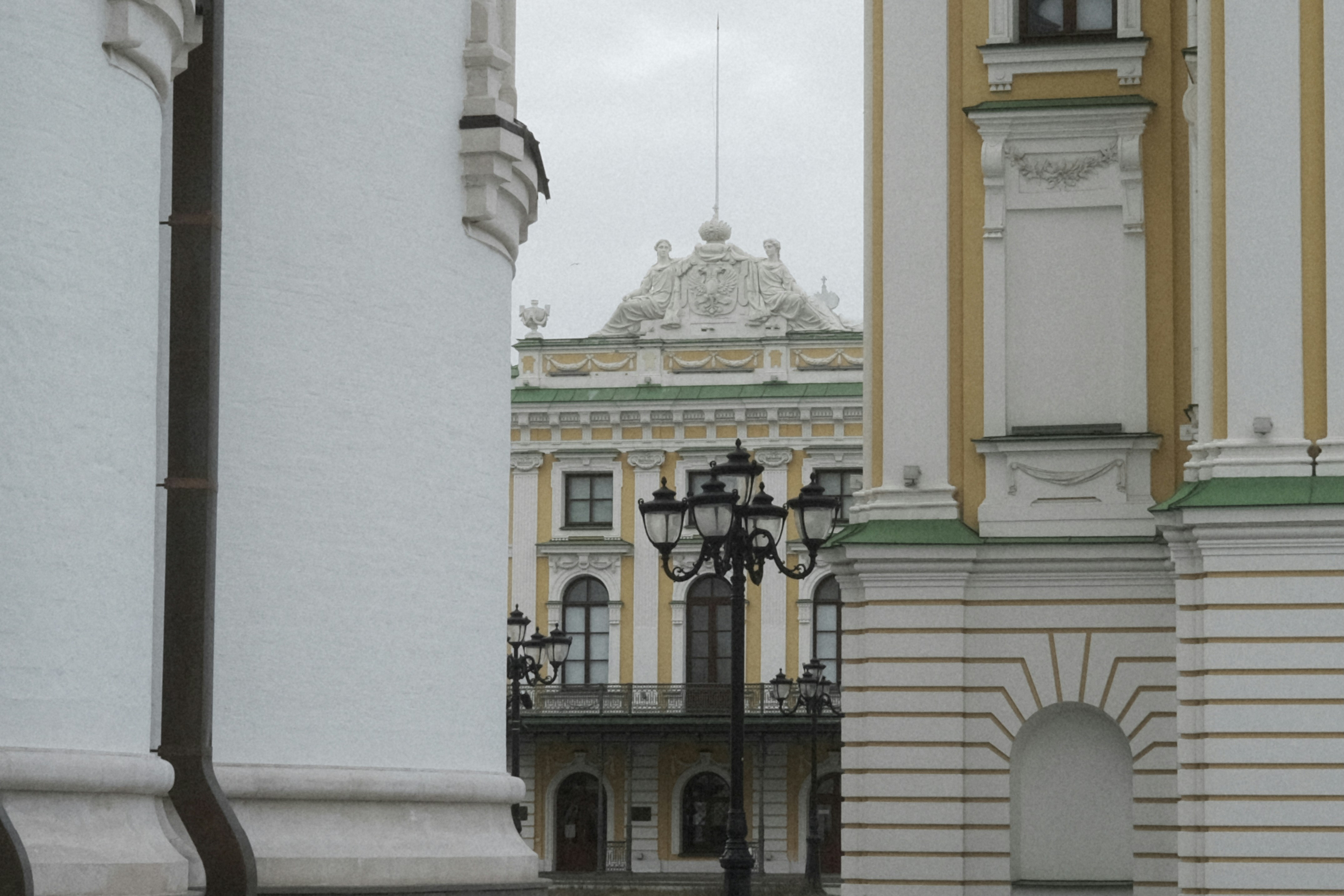 Ornate building facade framed by two towering structures under an overcast sky.