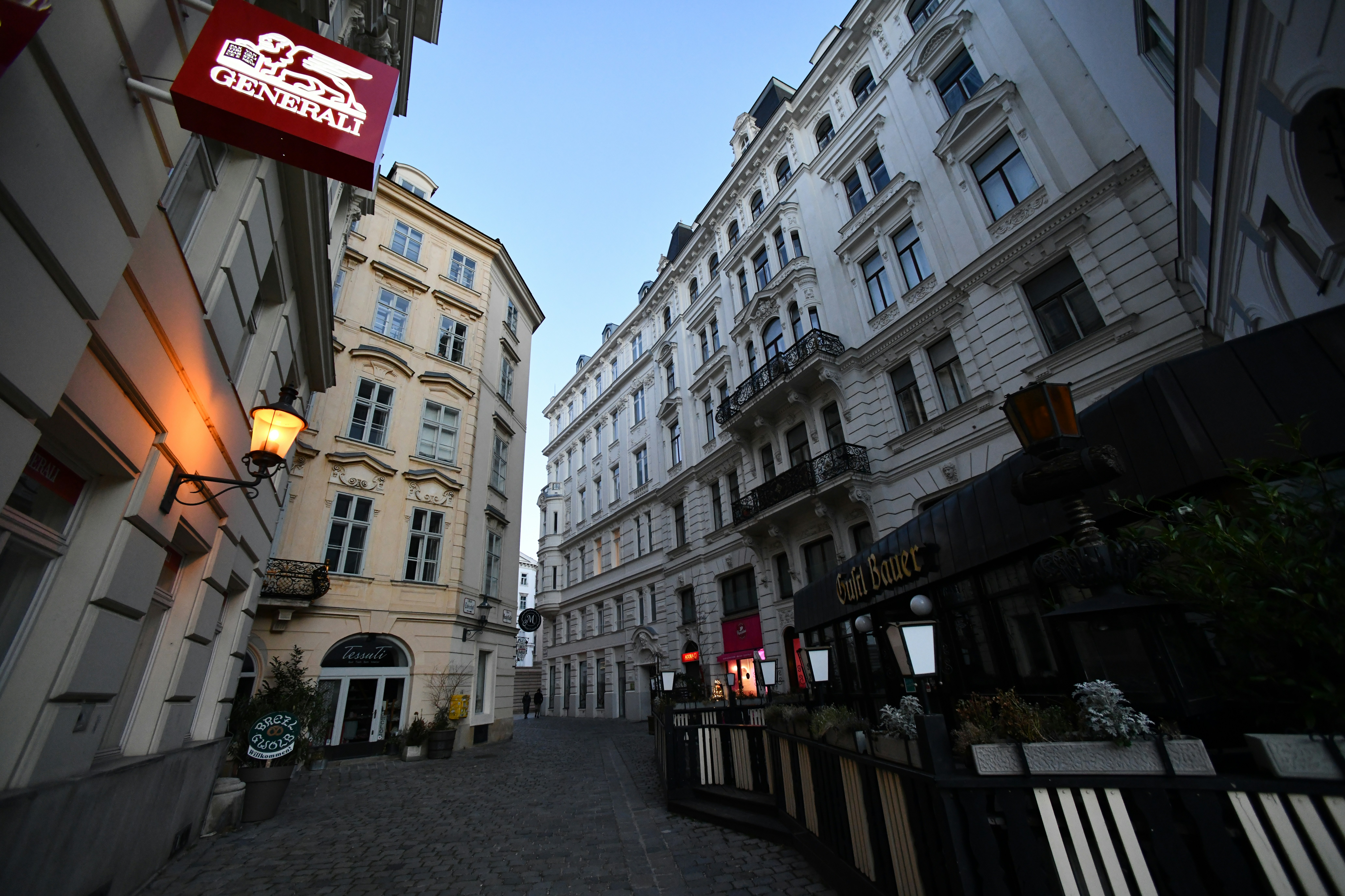 Narrow European street flanked by historic buildings under a twilight sky.