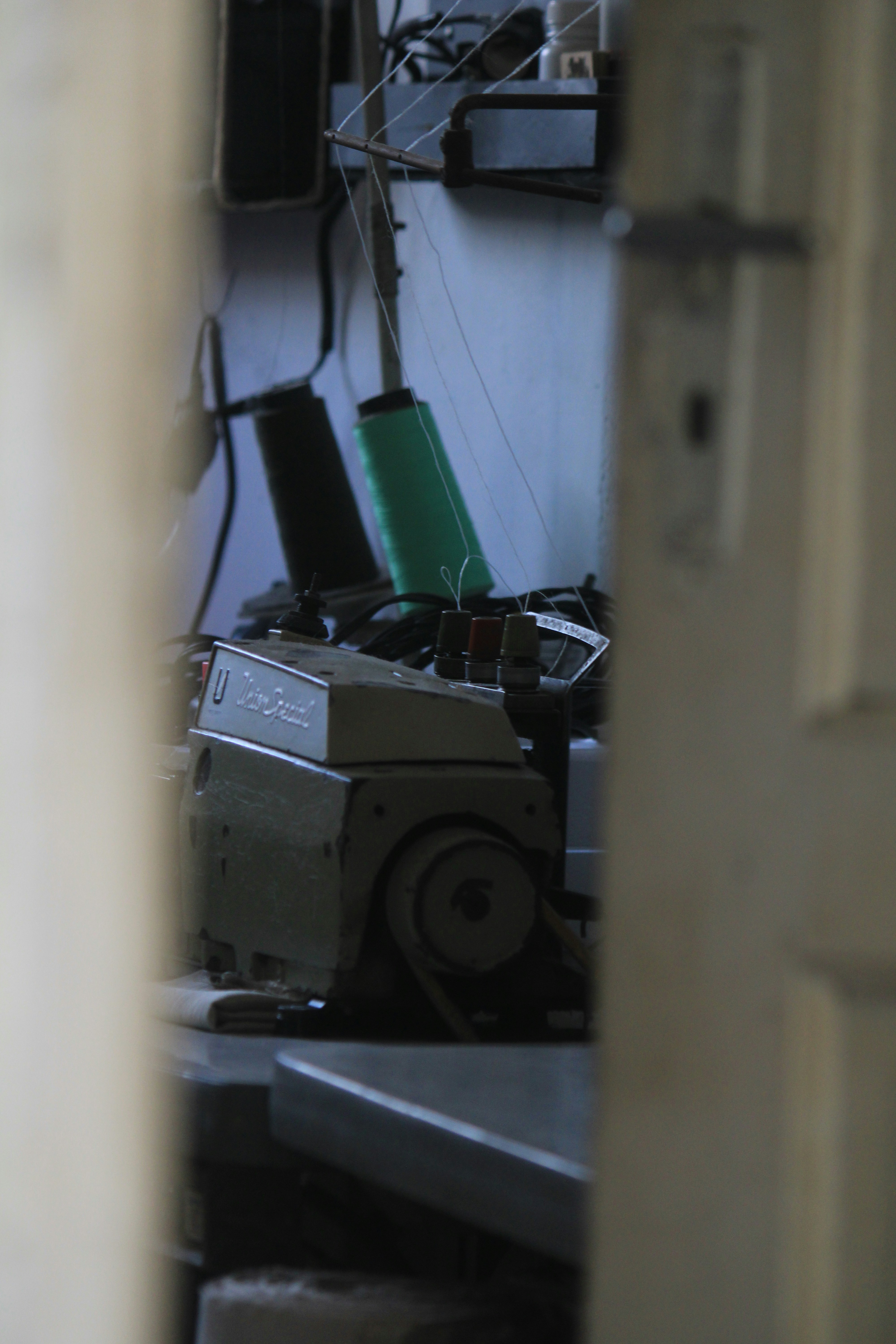 Sewing machine and spools of thread seen through a slightly open door.