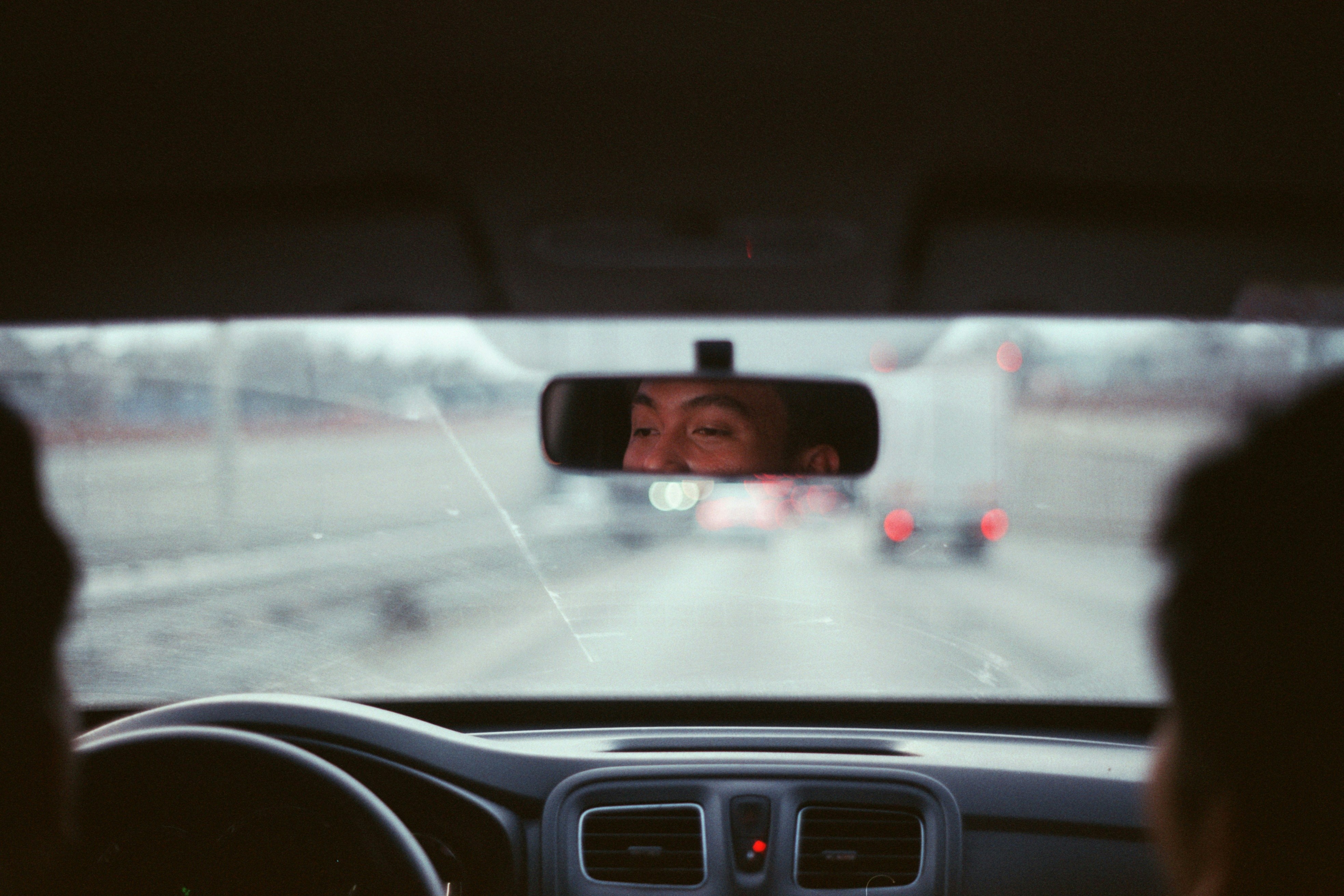 Photo of a man eyes driving from the middle rear view mirror. Photo was shot on film (fujifil superia 400)