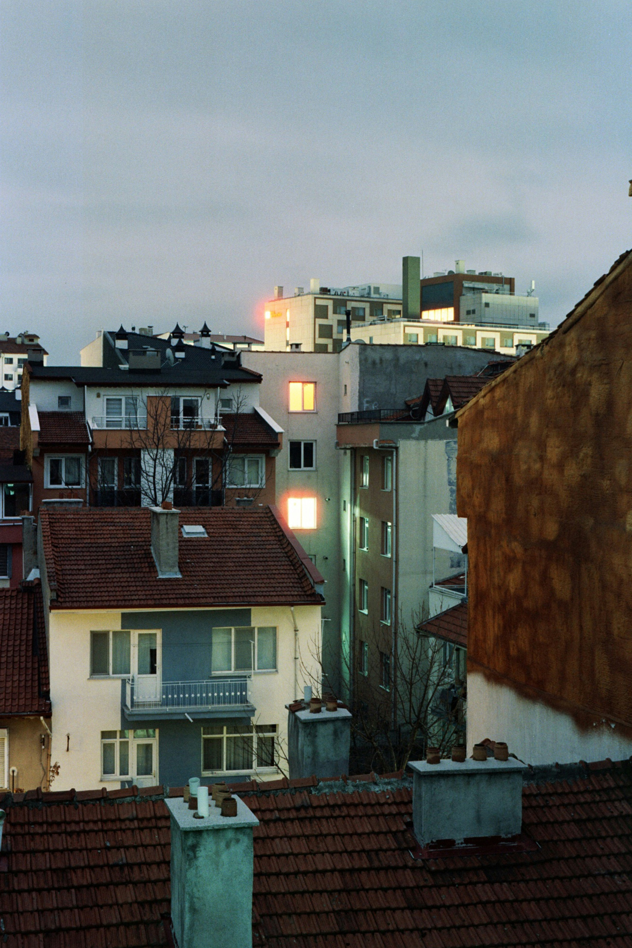Apartment buildings with a solitary glowing window amidst dusk shadows.