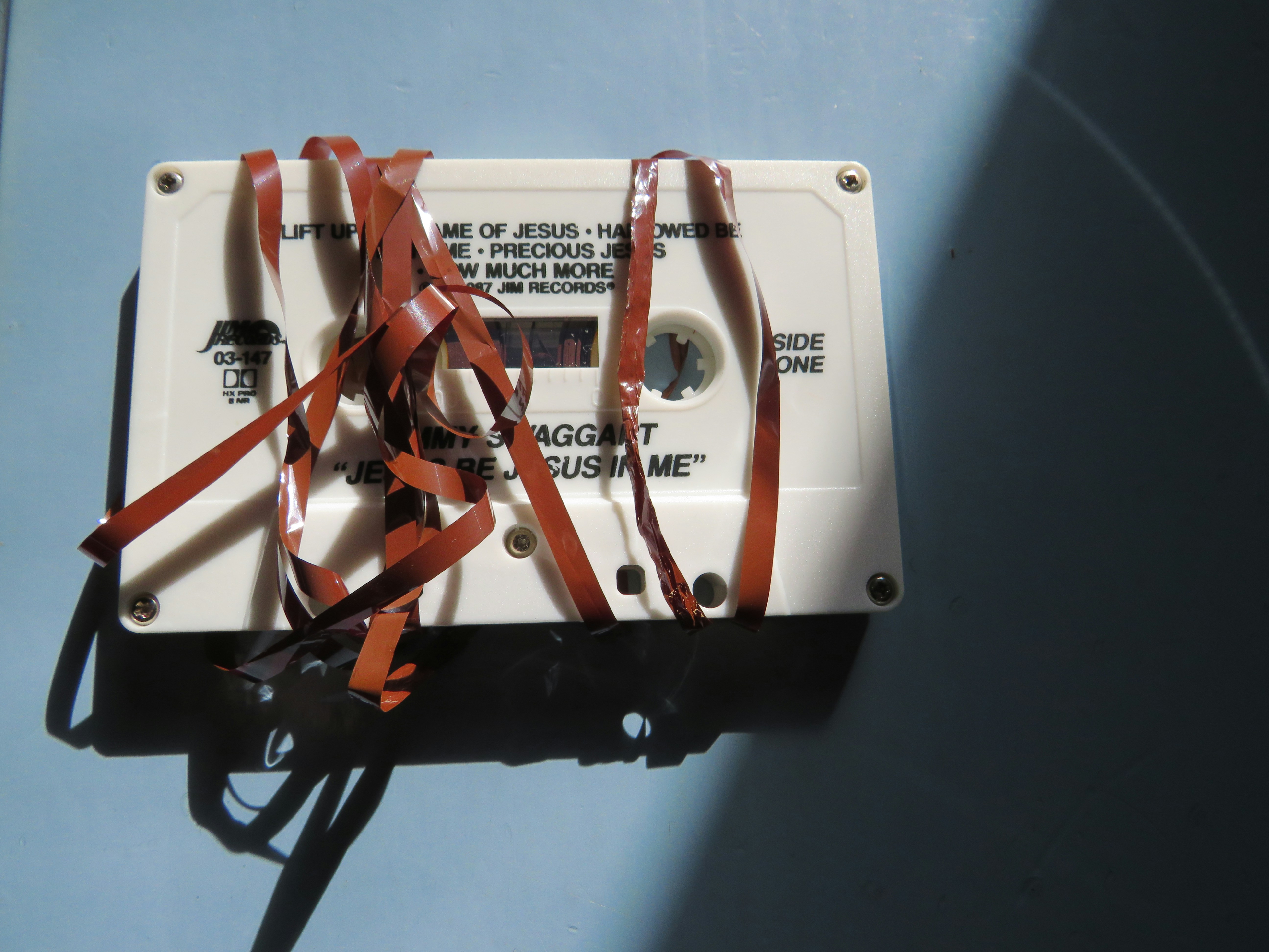 A broken cassette tape sits on a blue surface. photo – Free Sadness ...