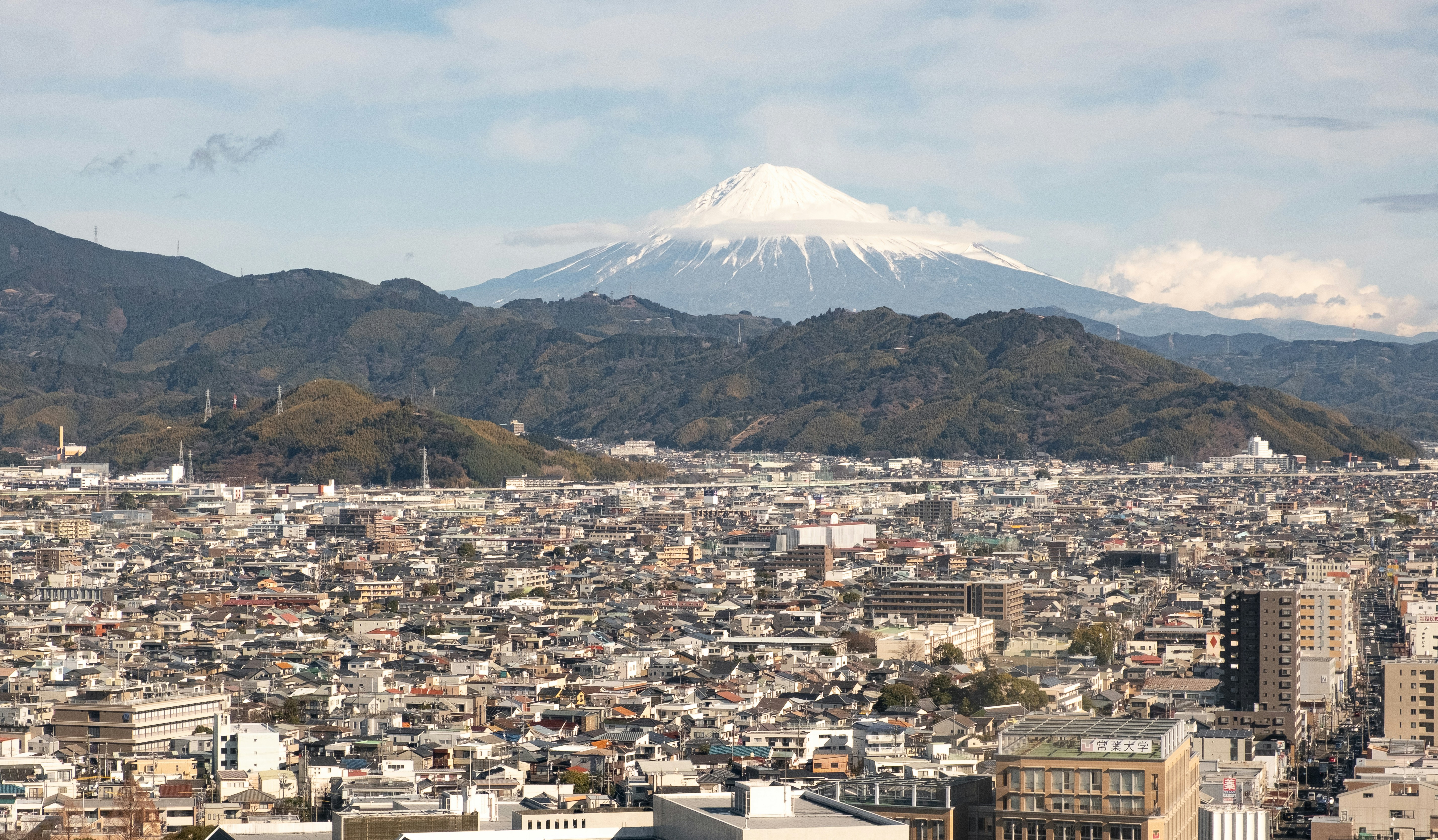 Expansive cityscape with Mount Fuji in the background under a clear sky.