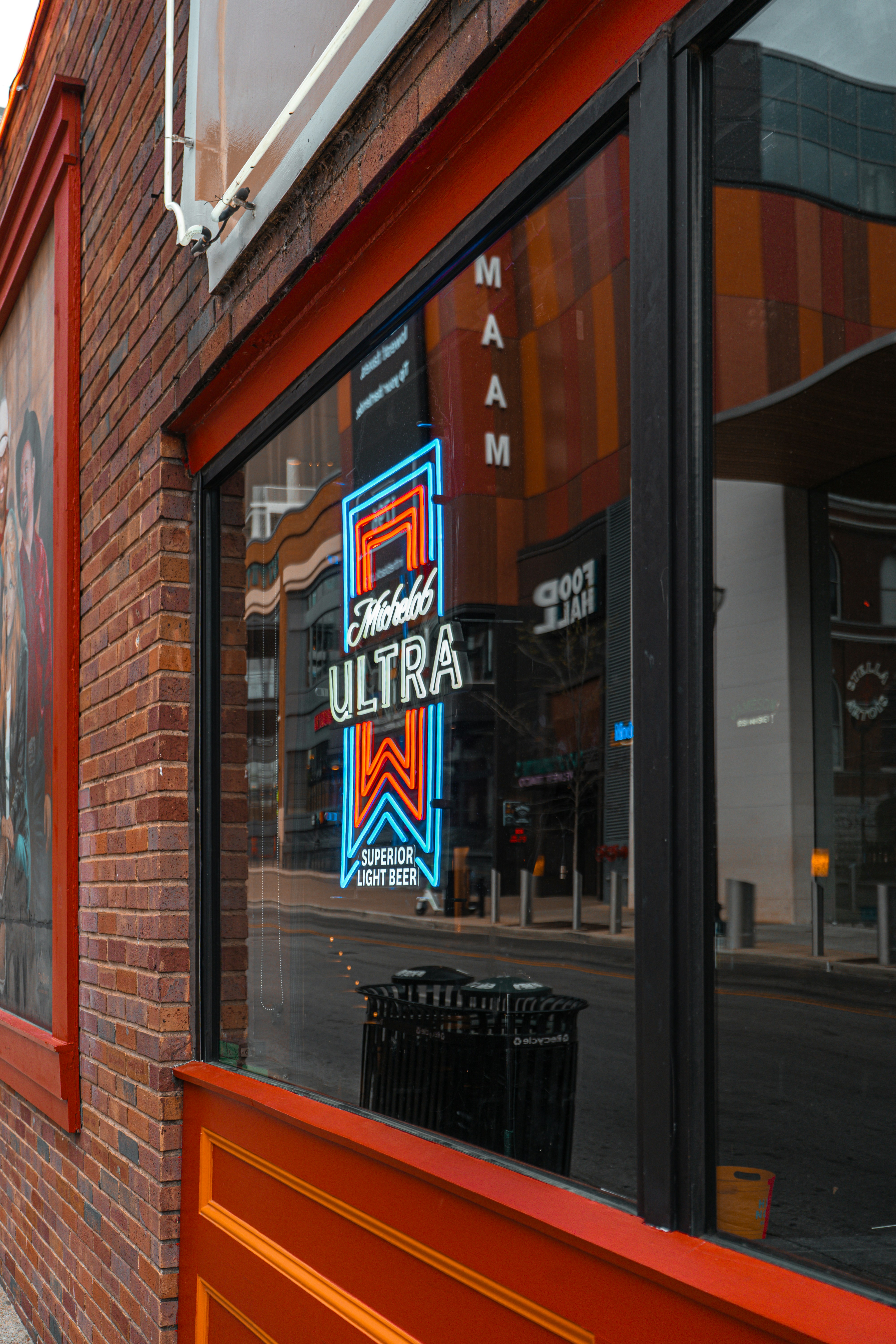 Colorful storefront window reflecting urban street scene with bold signage and architectural details.