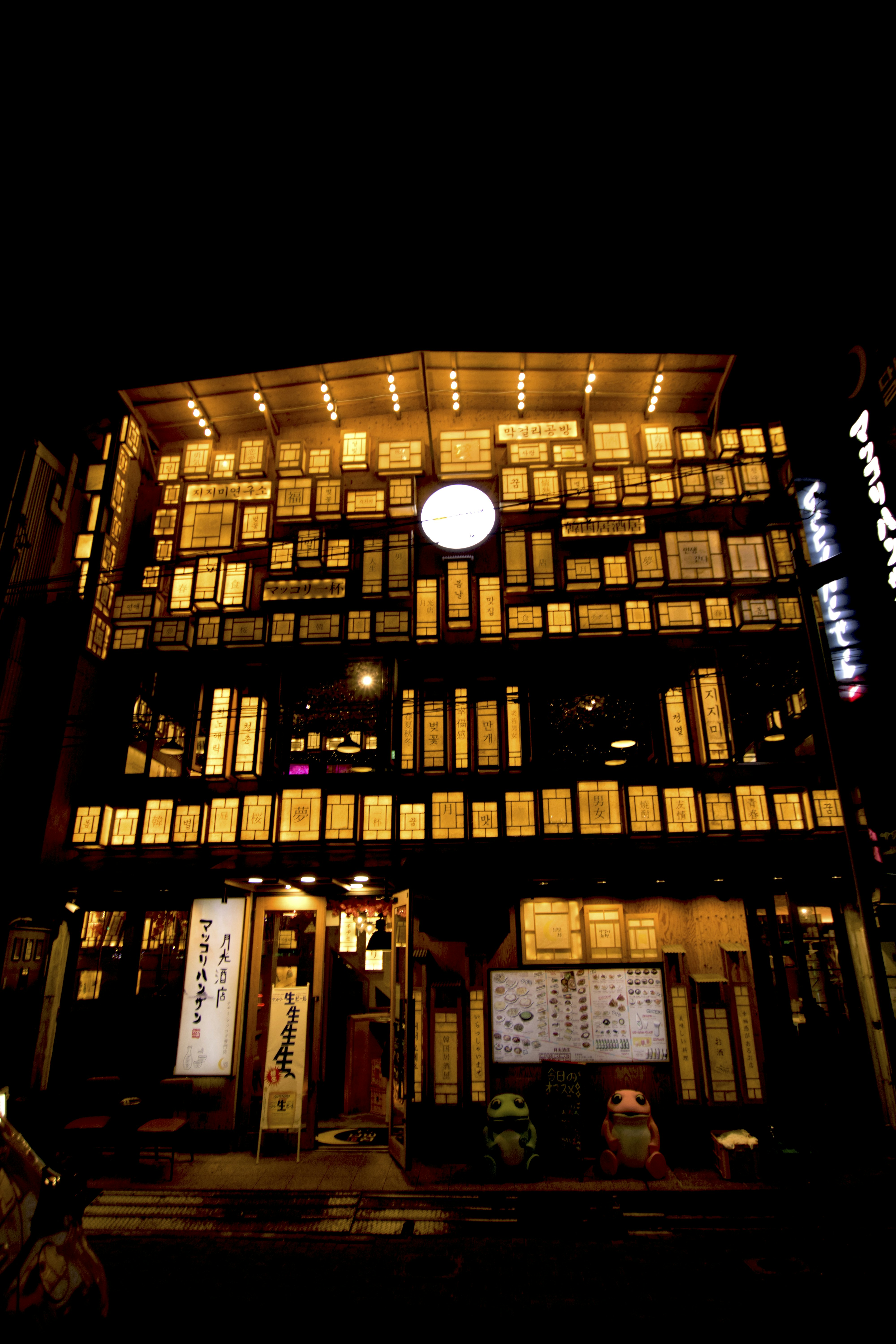 Multi-story building adorned with warm yellow lights and signage against a nighttime backdrop.
