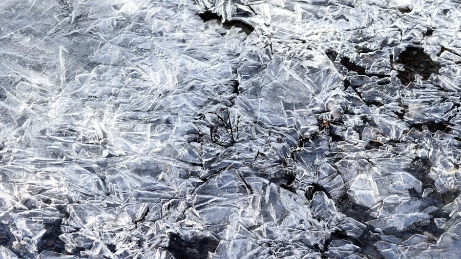 Cracked, translucent ice sheets layered over a dark frozen surface, with bright highlights and jagged textures throughout.