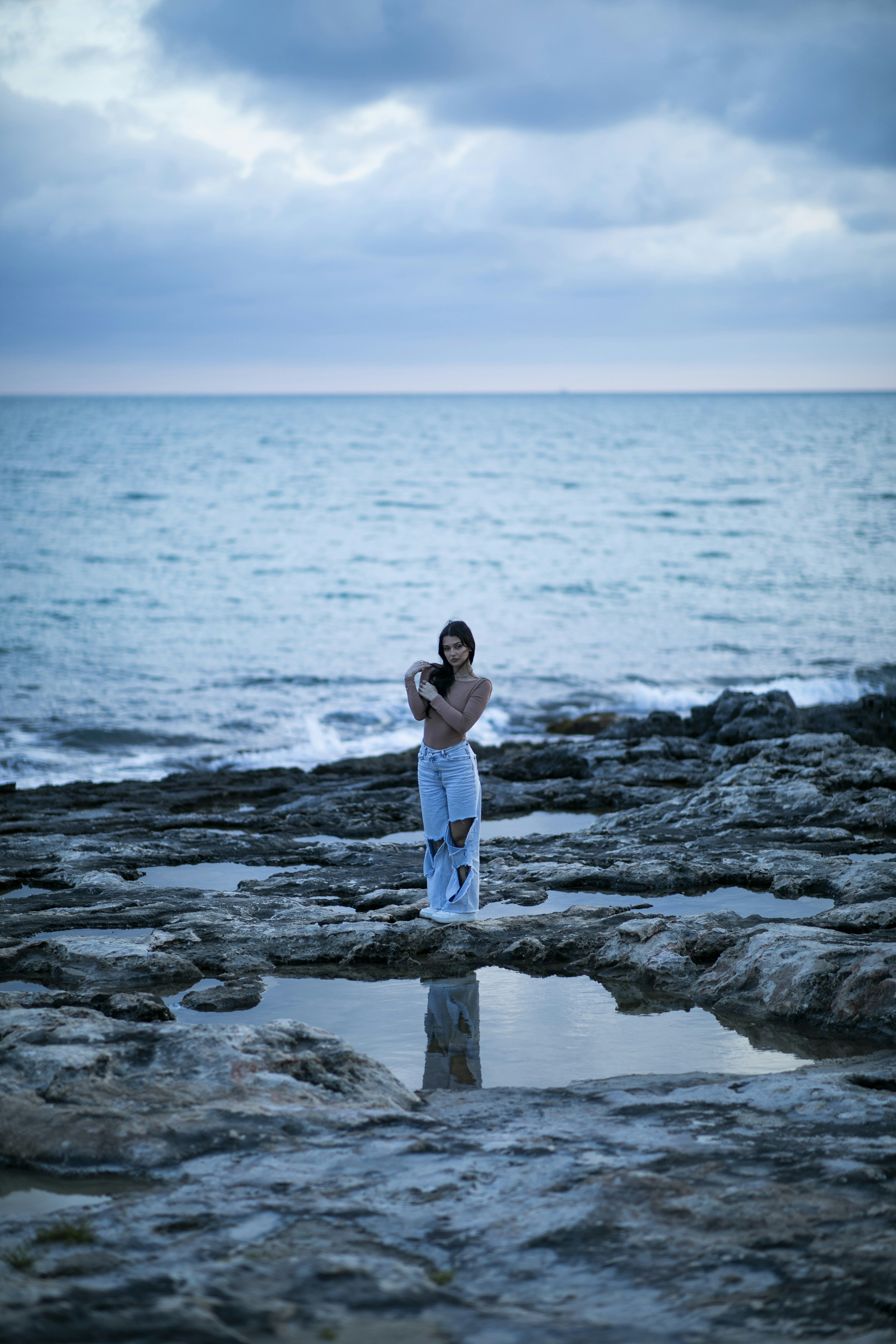 Woman stands by the ocean in the dim light. photo – Free Beach Image on ...