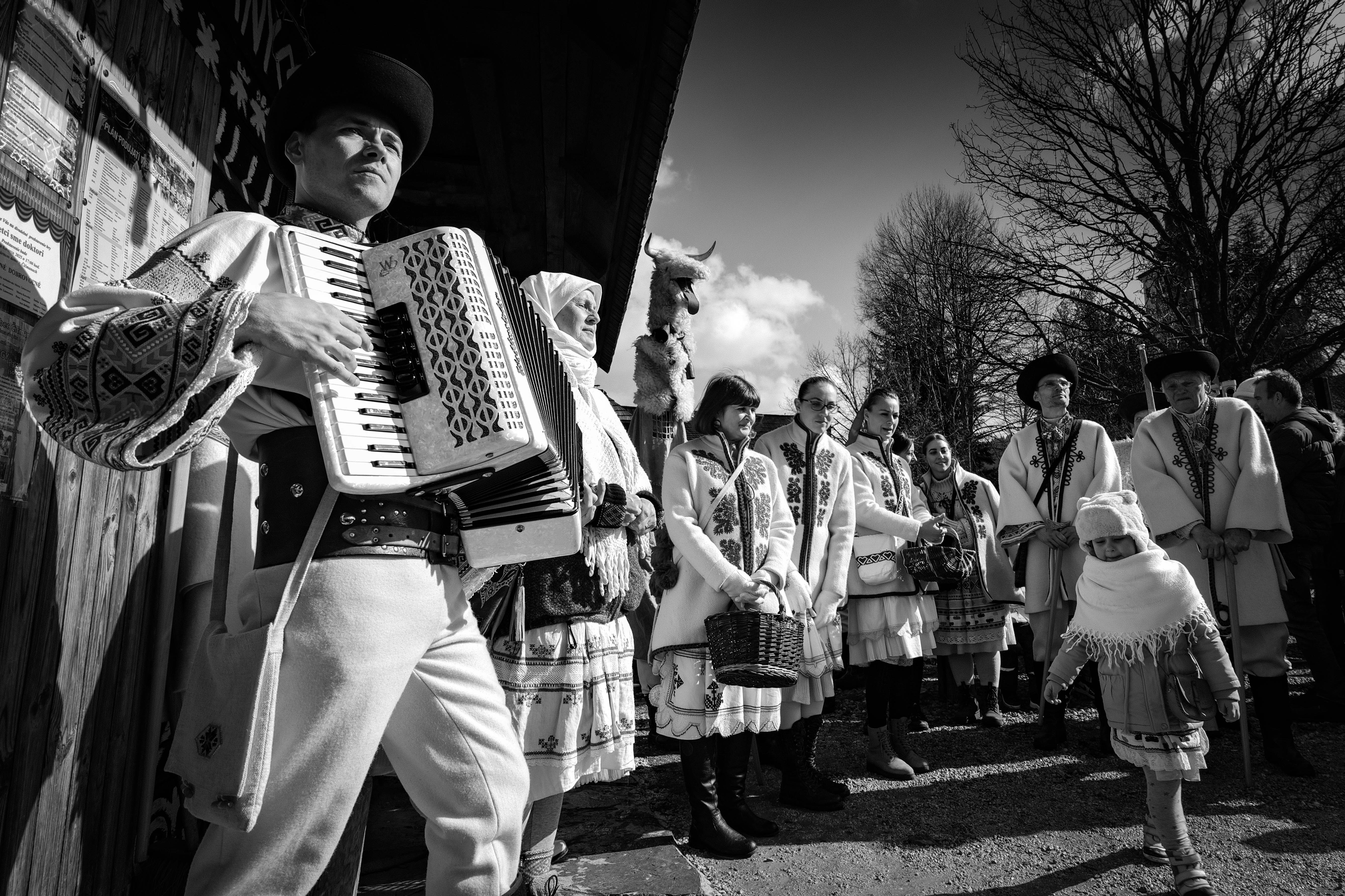 Musician plays accordion alongside traditionally dressed people during a Slovak folk festival in Čičmany.